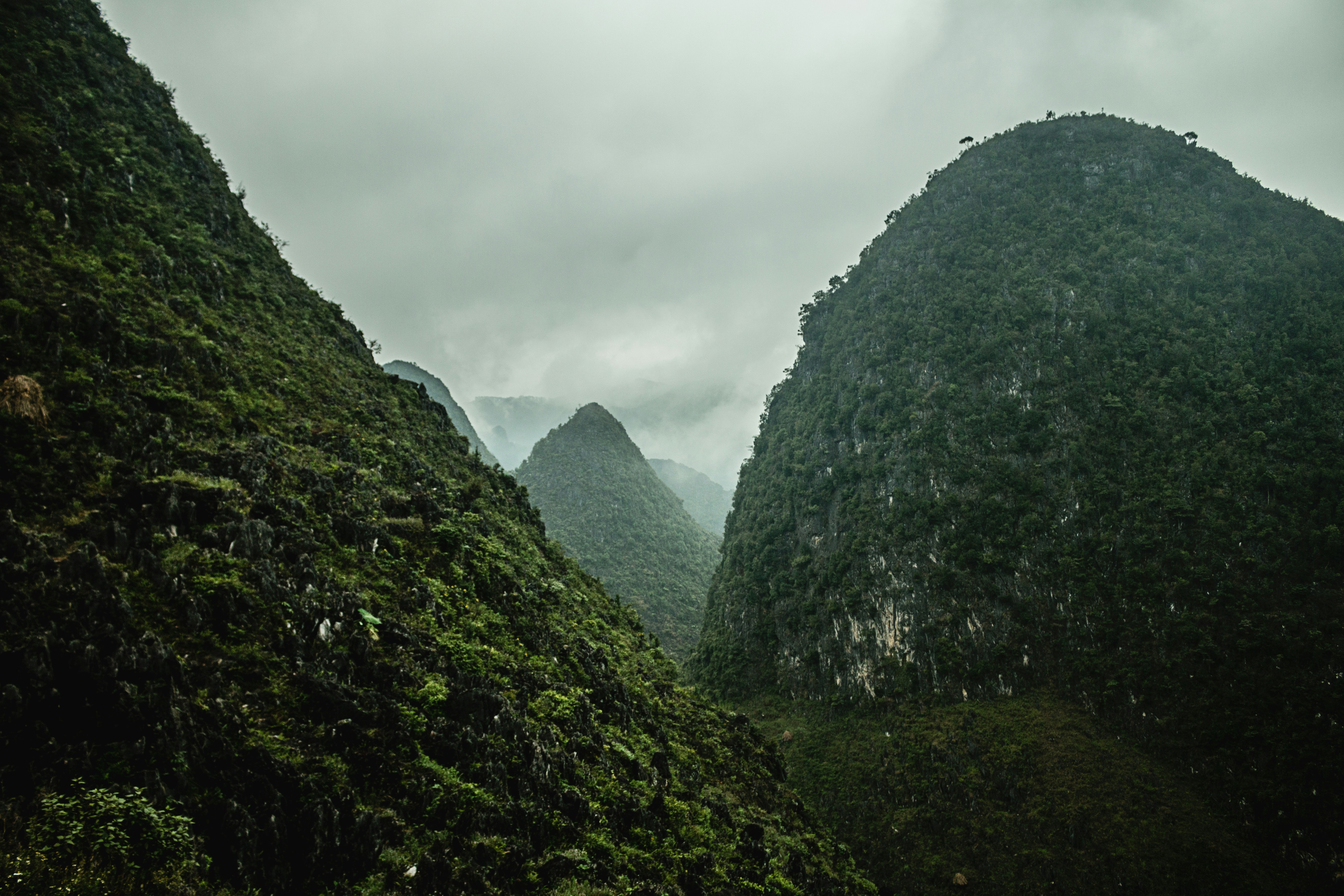Lush green mountains shrouded in mist create a mysterious landscape, highlighting the rugged beauty of the terrain. The scene evokes a sense of solitude and tranquility.