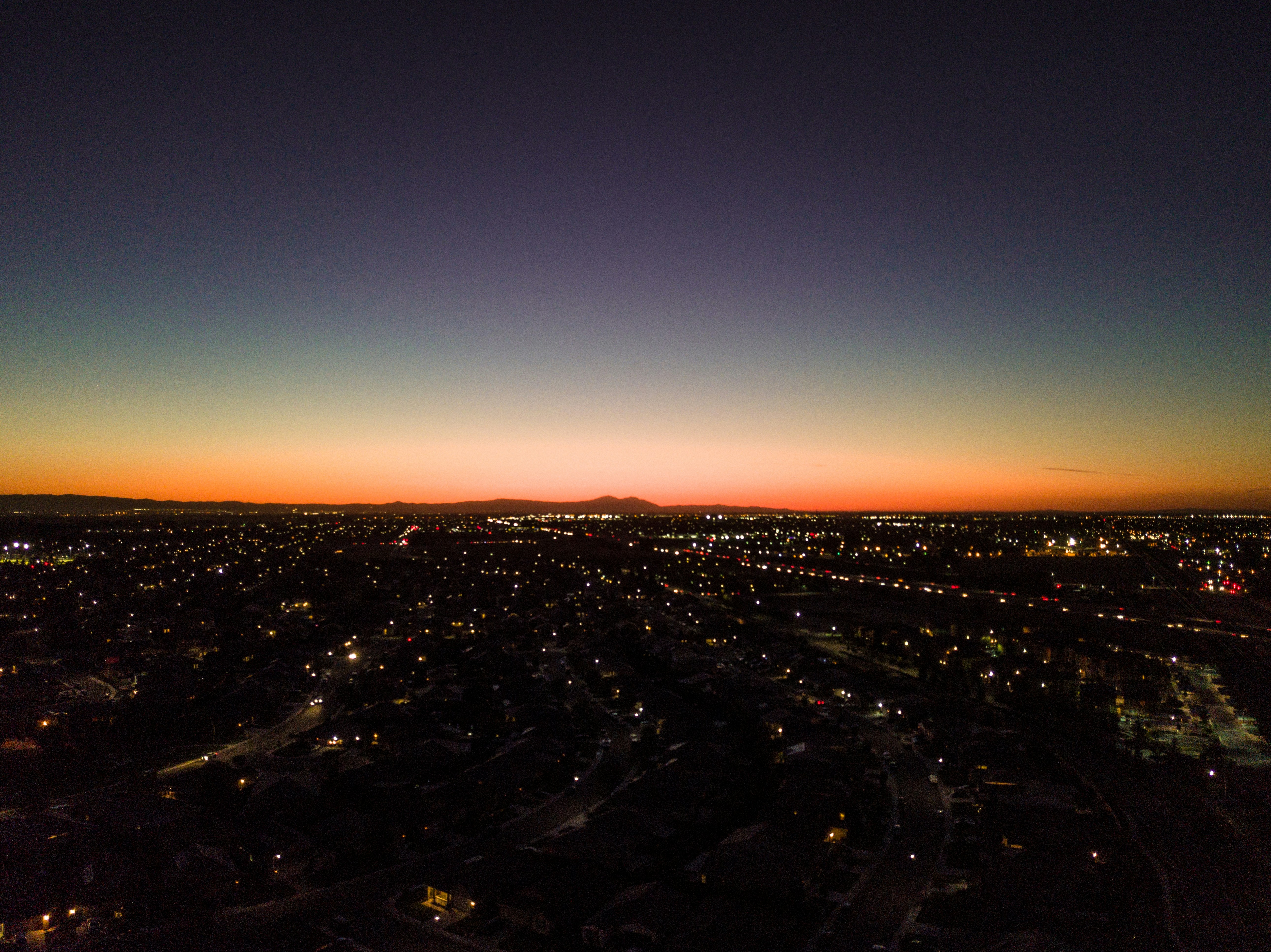 City skyline under a gradient sky transitioning from orange to deep blue.