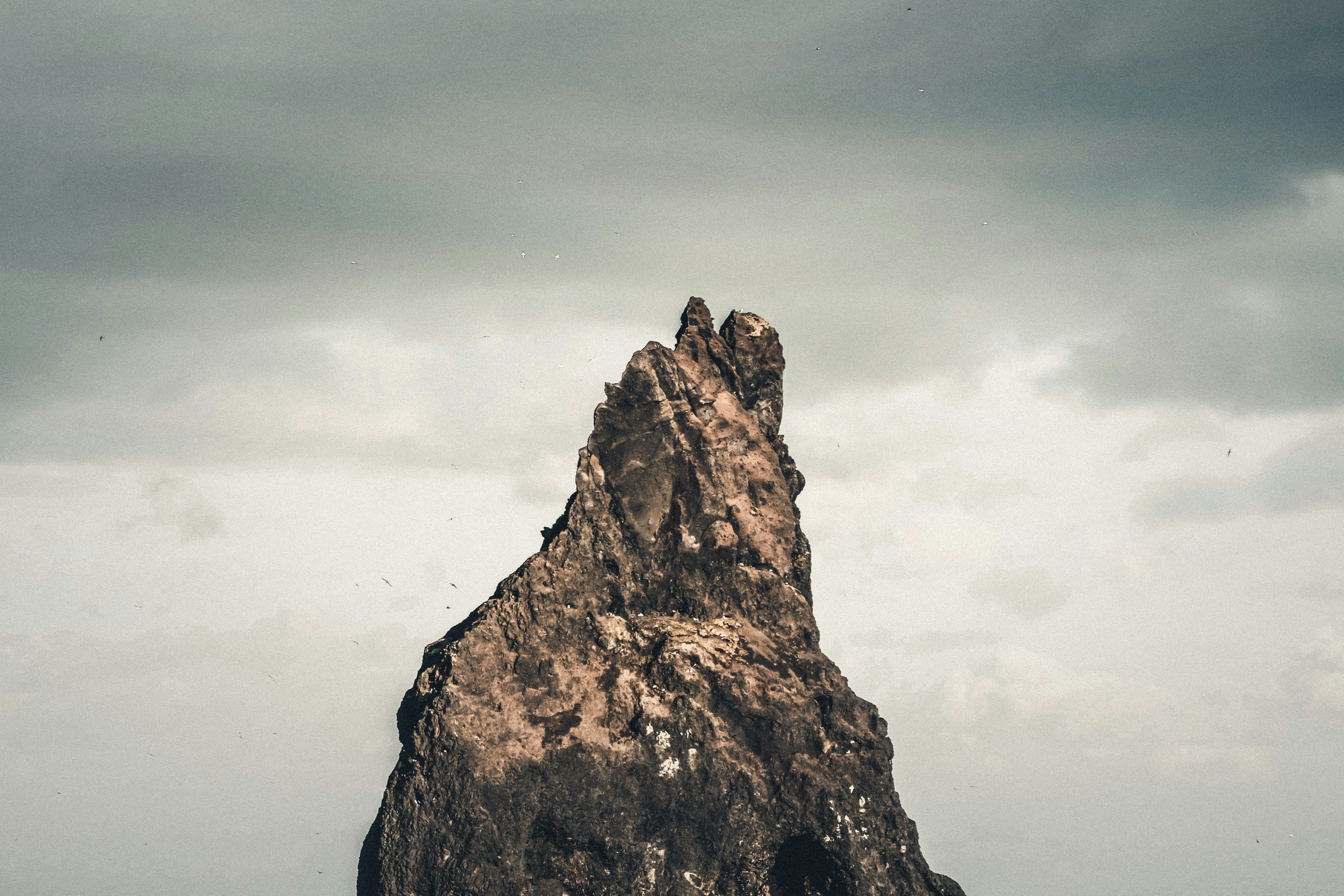 A solitary rock formation rises dramatically against a moody sky, embodying the rugged beauty of coastal landscapes.