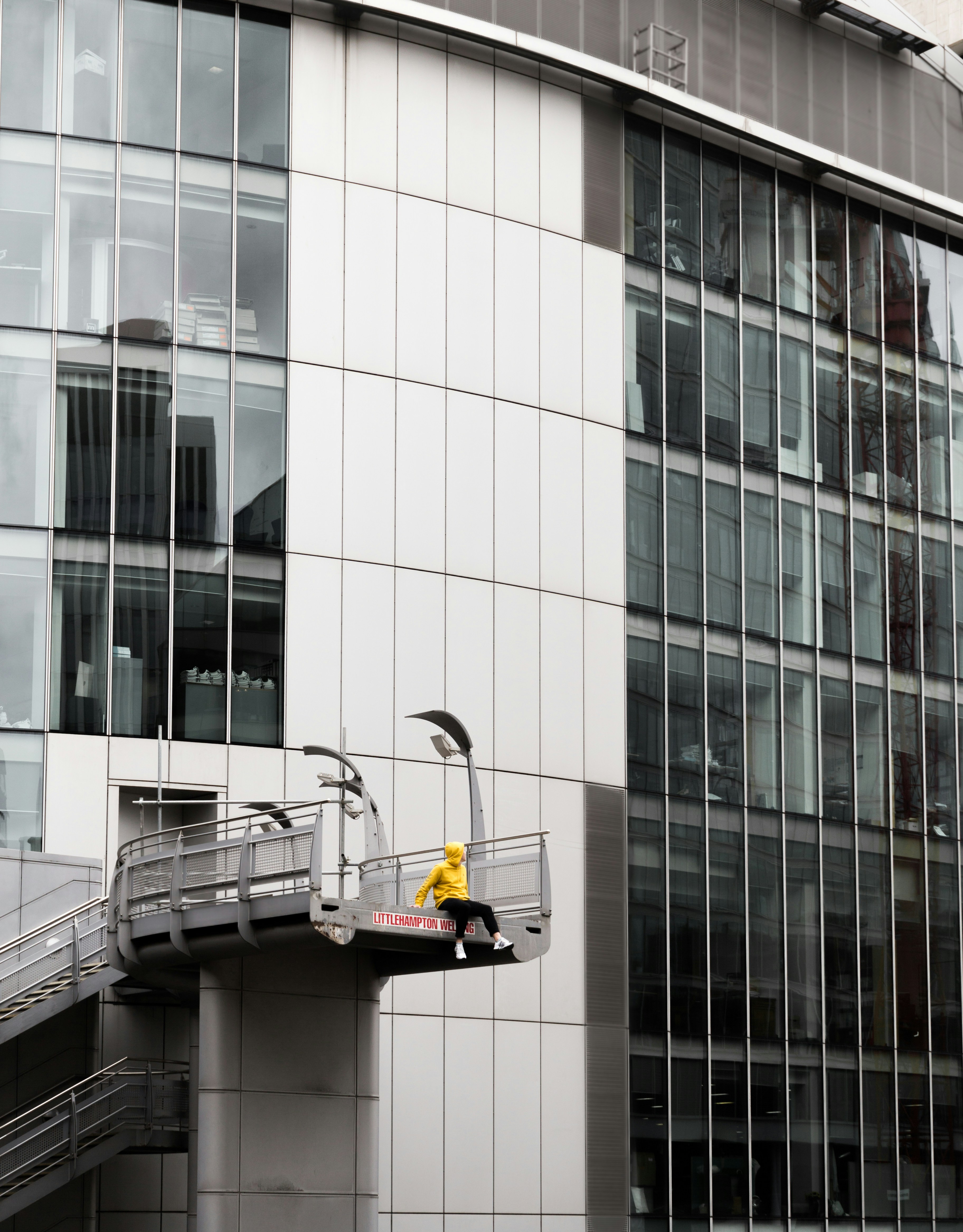 Person sitting on edge of bridge near building during daytime photo ...