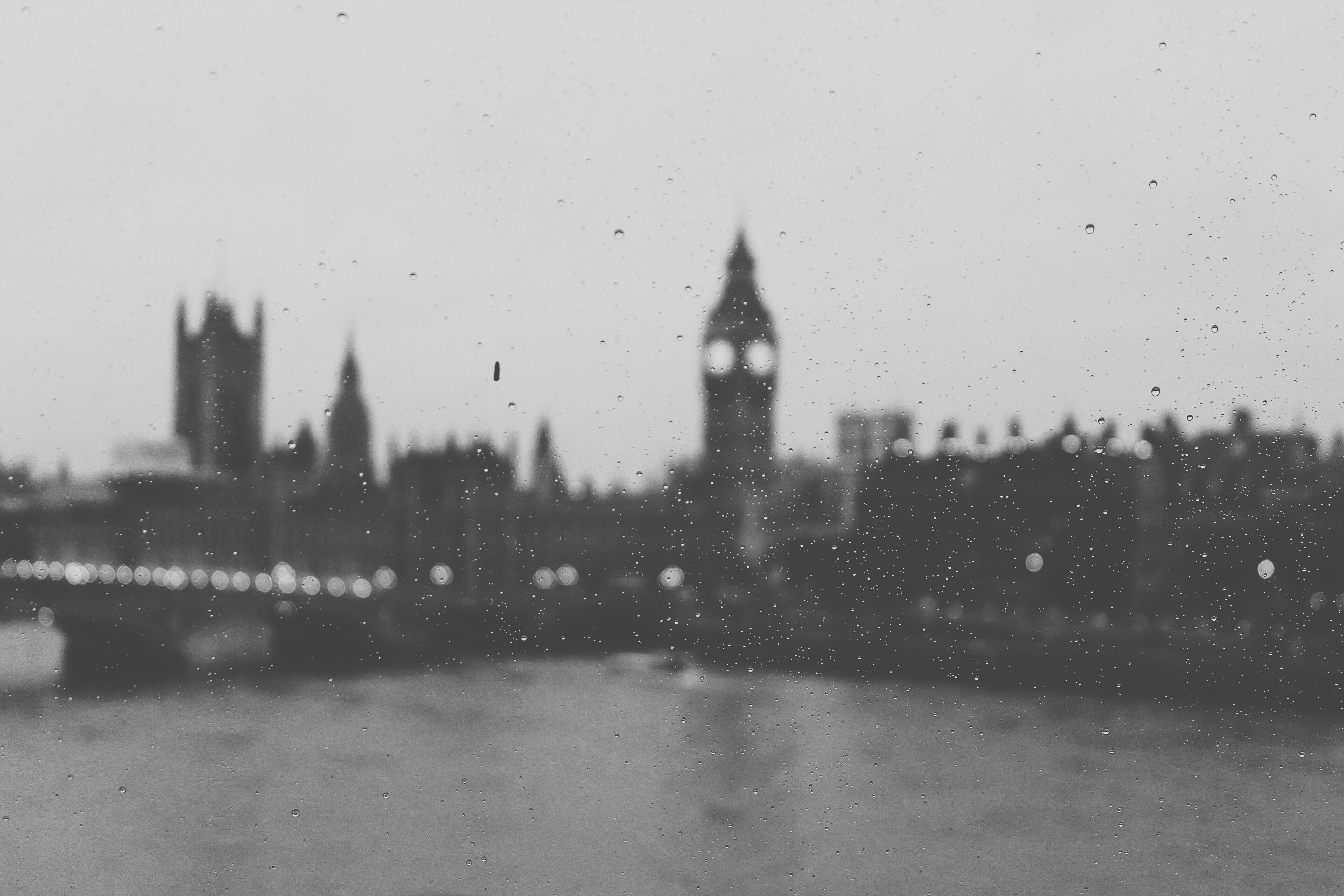 Blurred cityscape of London with the River Thames and iconic clock tower under a gray sky.
