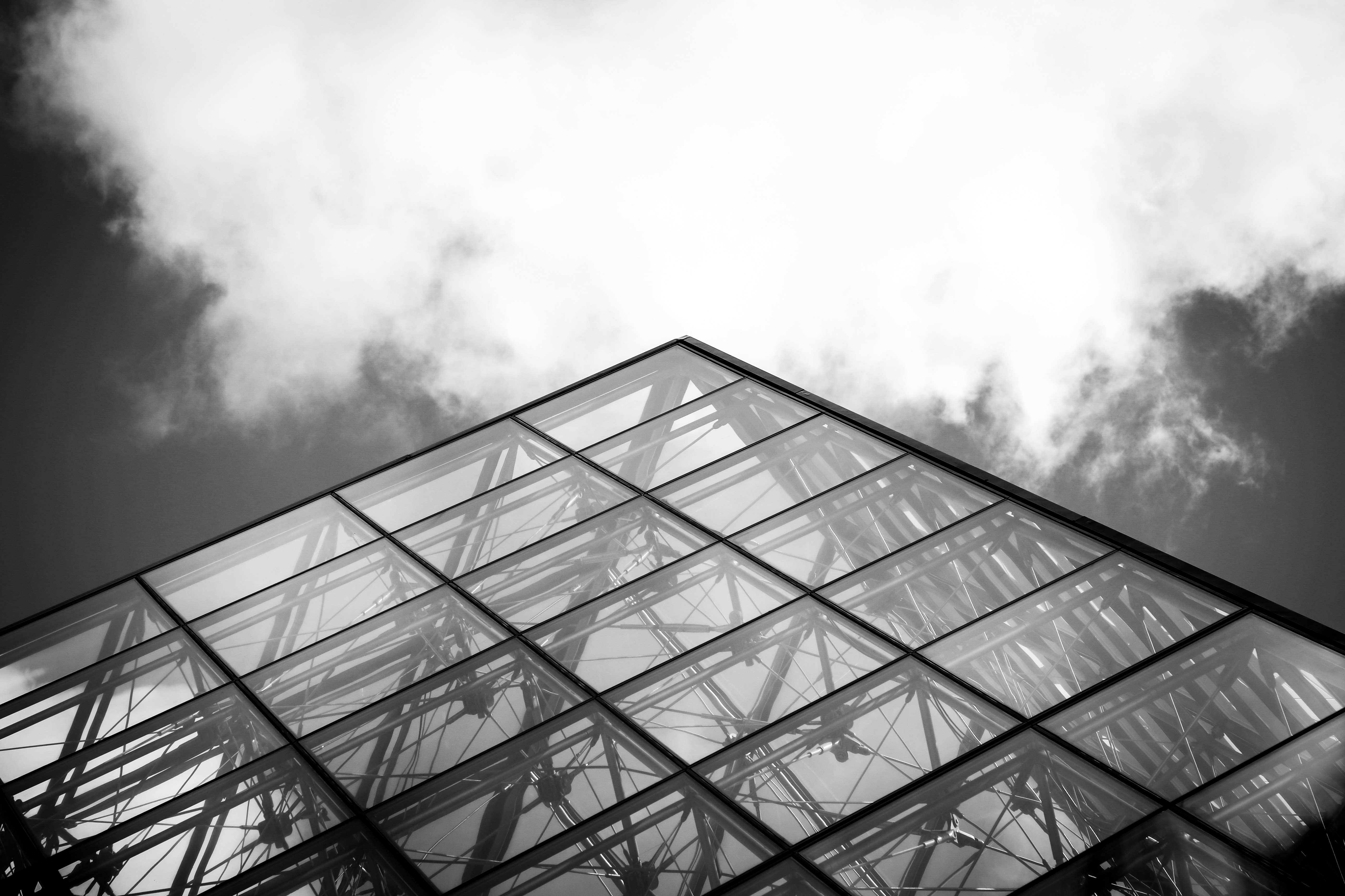 Glass pyramid structure against a cloudy sky.