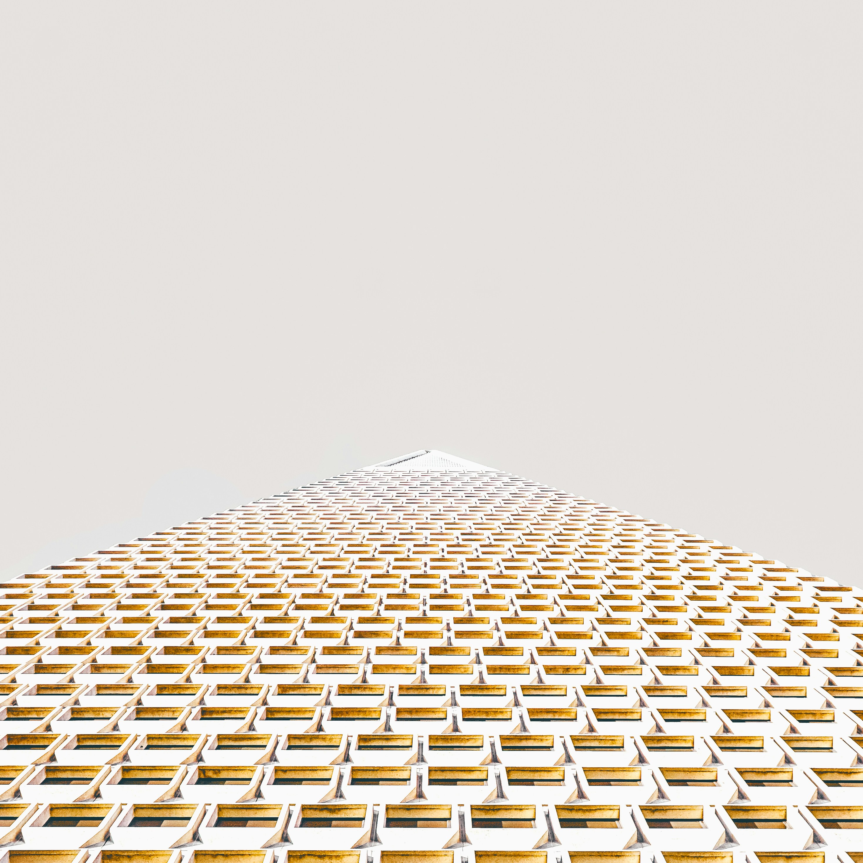 A towering architectural structure with a patterned facade, viewed from a low angle, emphasizing its height and geometric design.