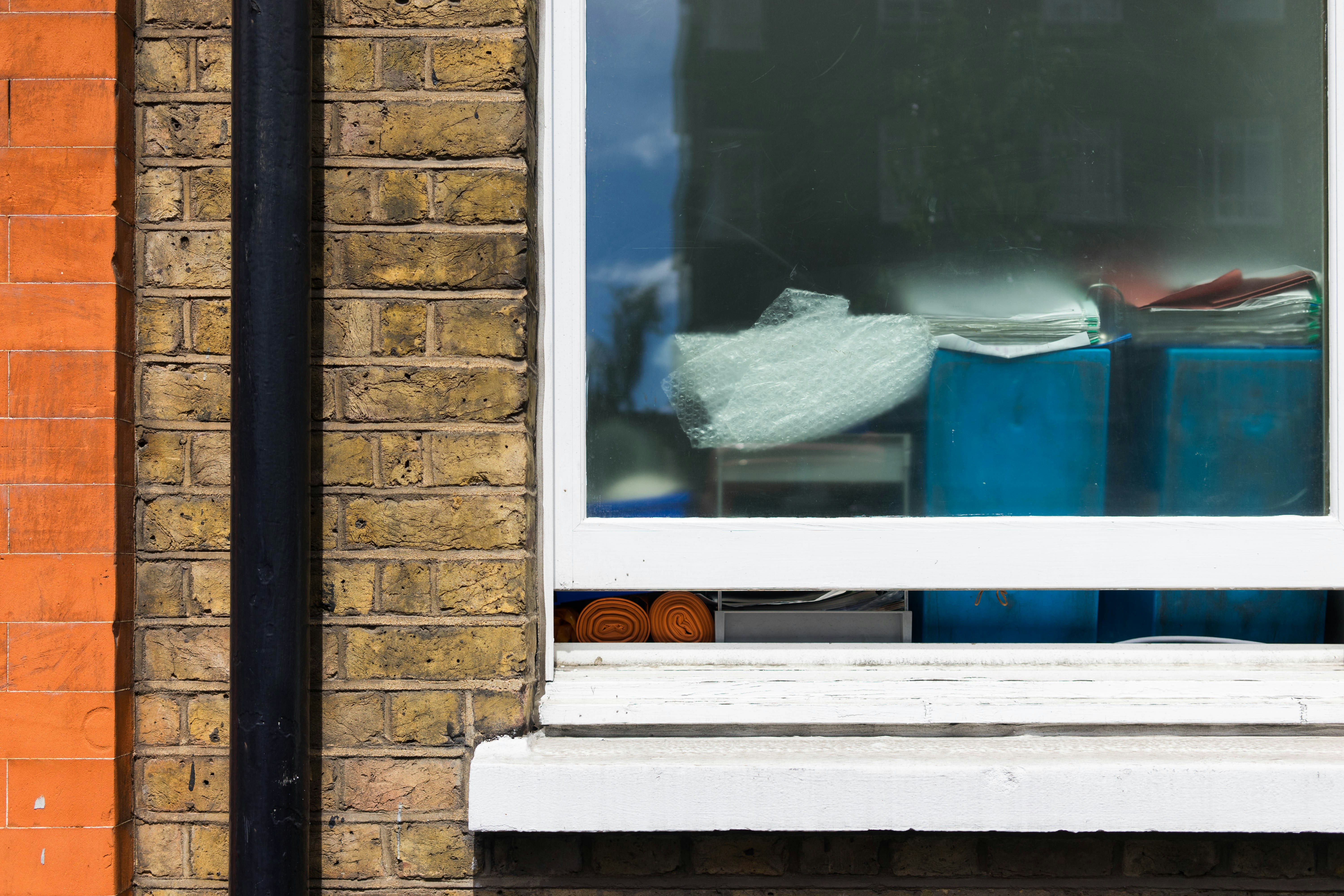 Windowed Quiet: Blue Boxes and White Linens Behind Brick Facade