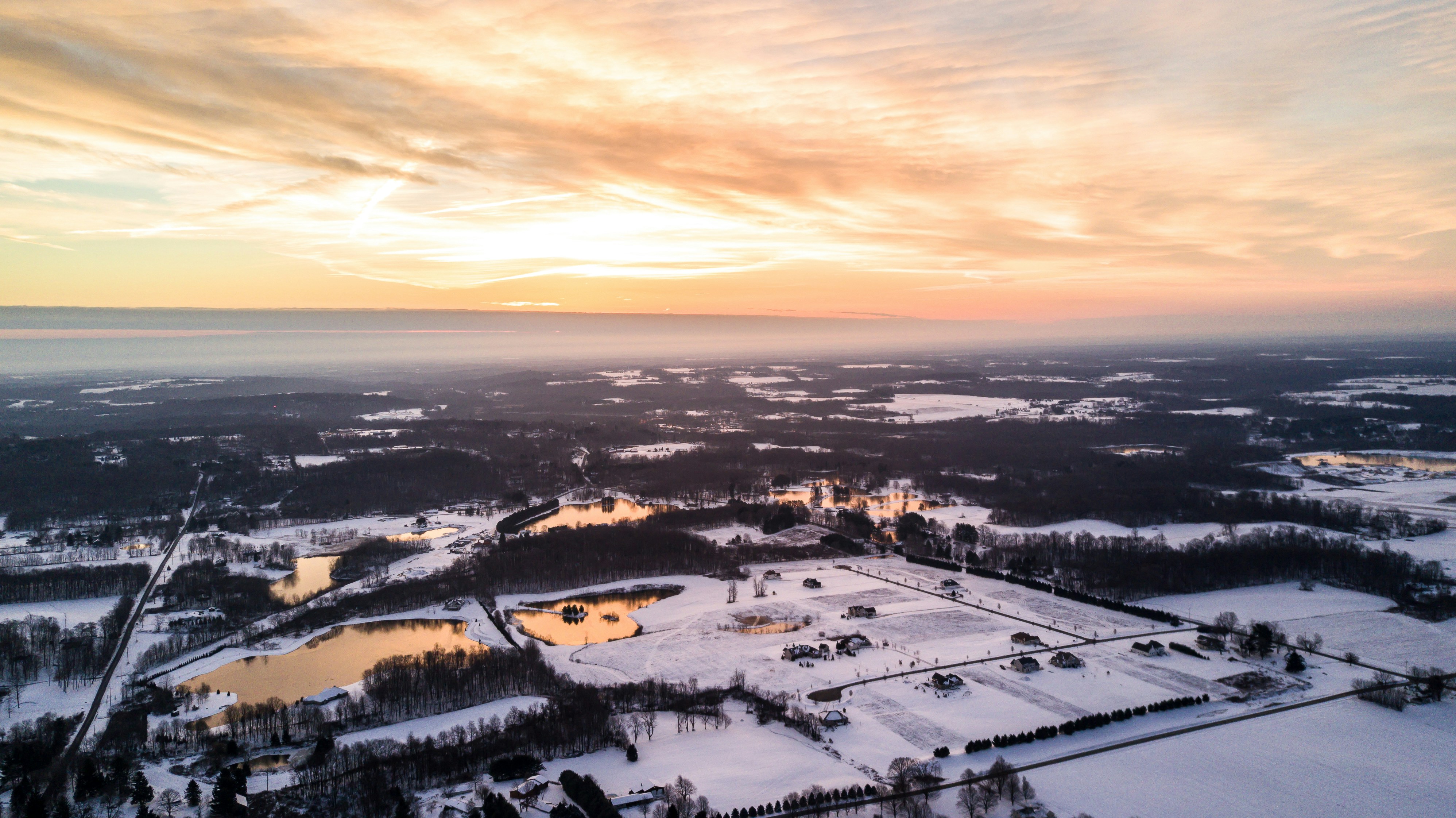 Snow-dusted fields and reflective lakes under a vibrant sunrise sky in Northeast Ohio.