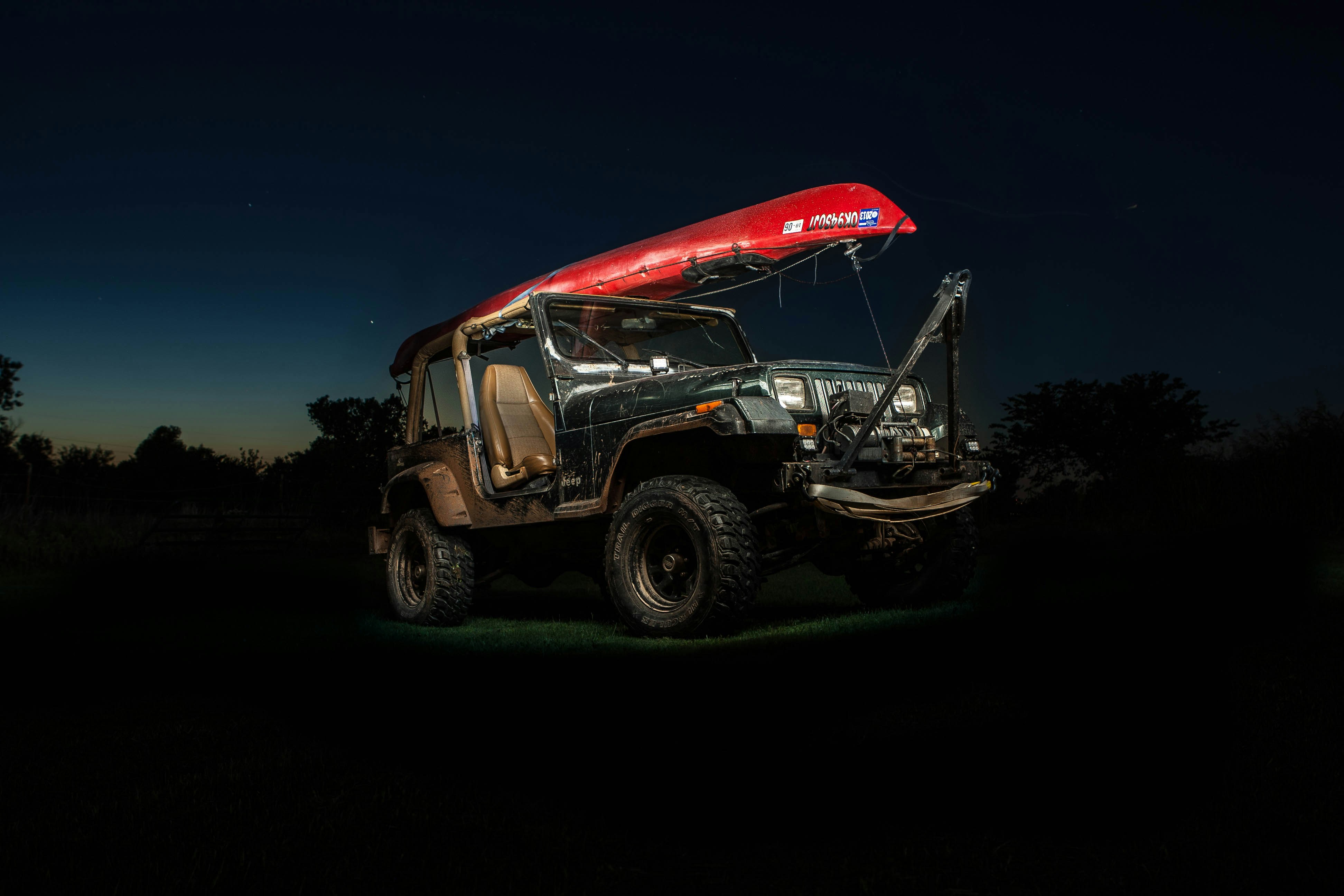 Off-road vehicle with a kayak mounted on top, set against a twilight backdrop. The scene captures the spirit of adventure and exploration.