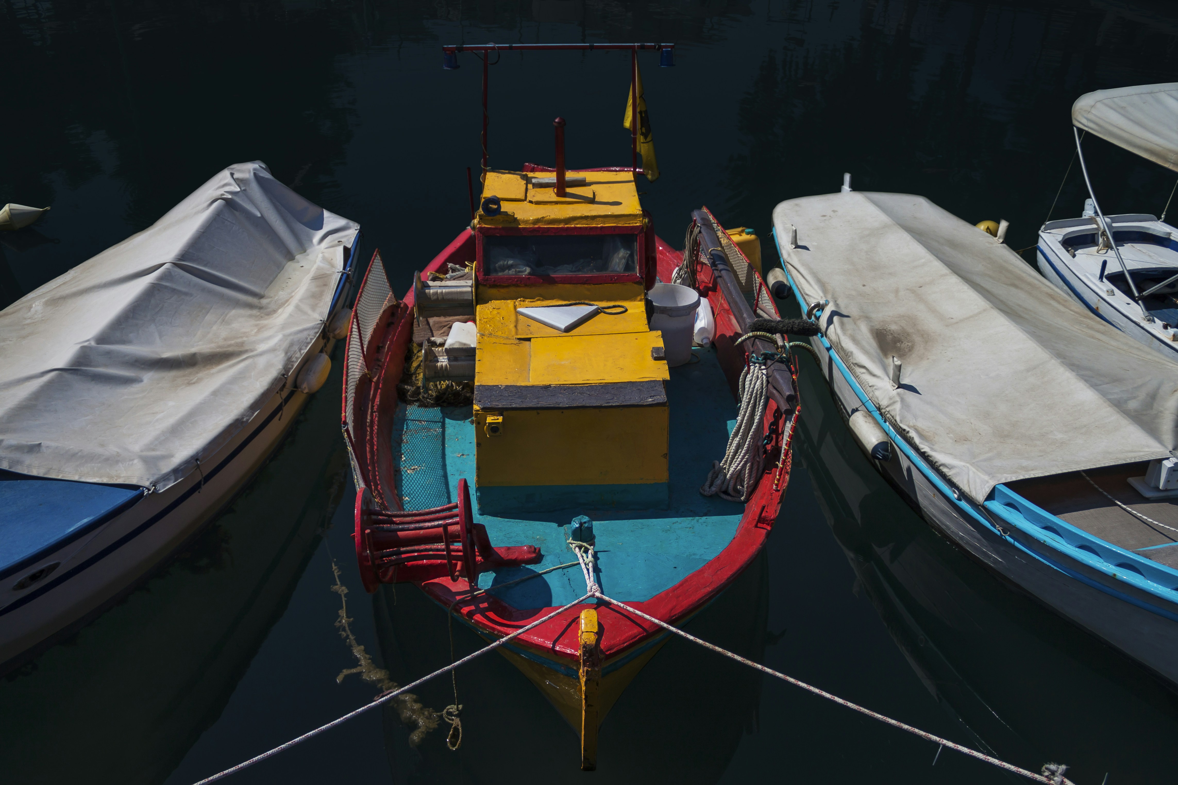 Colorful vintage fishing boats moored in a tranquil Greek harbor.