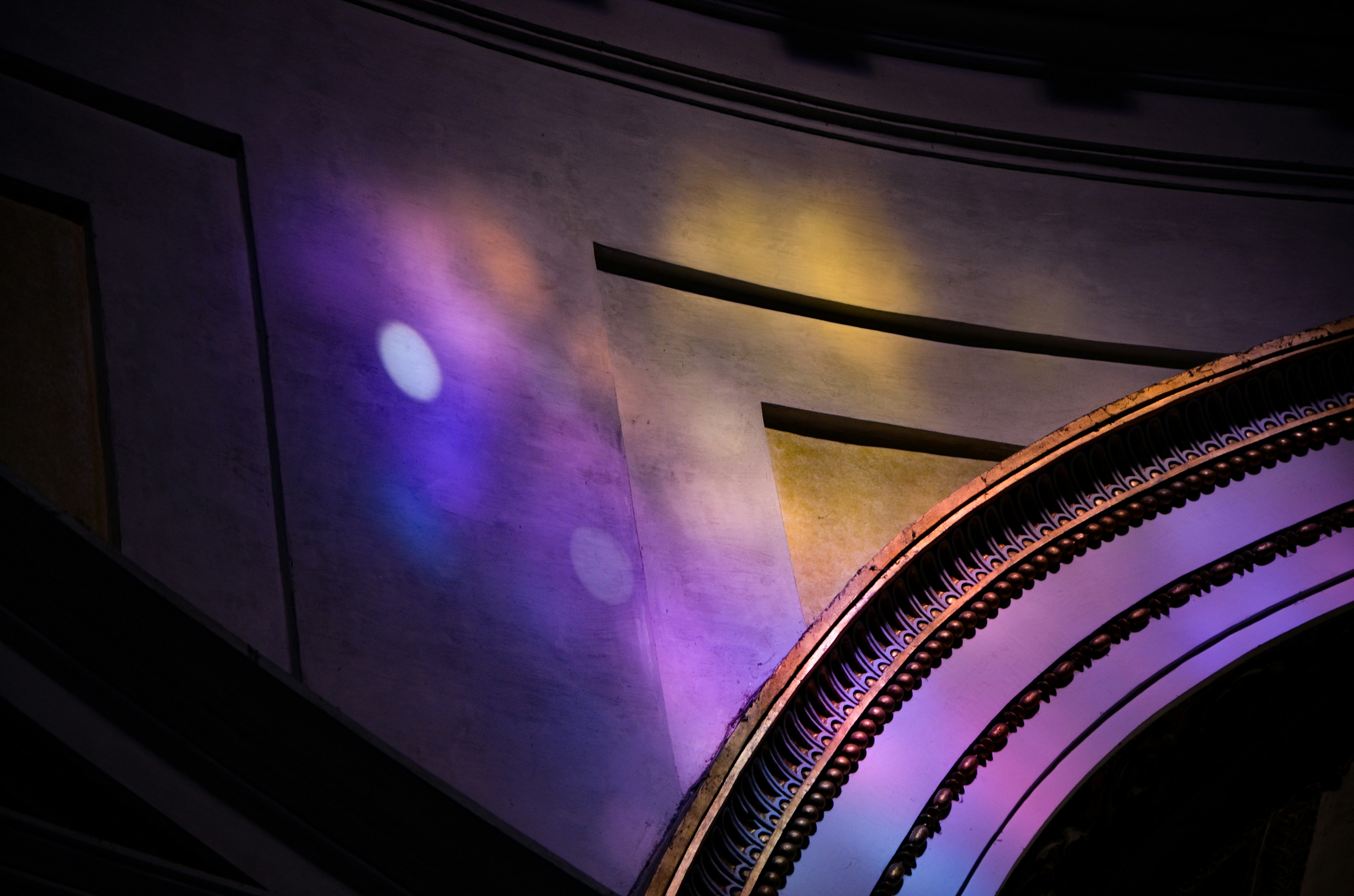 Colored light patterns dance across a curved wall, highlighting intricate architectural details.