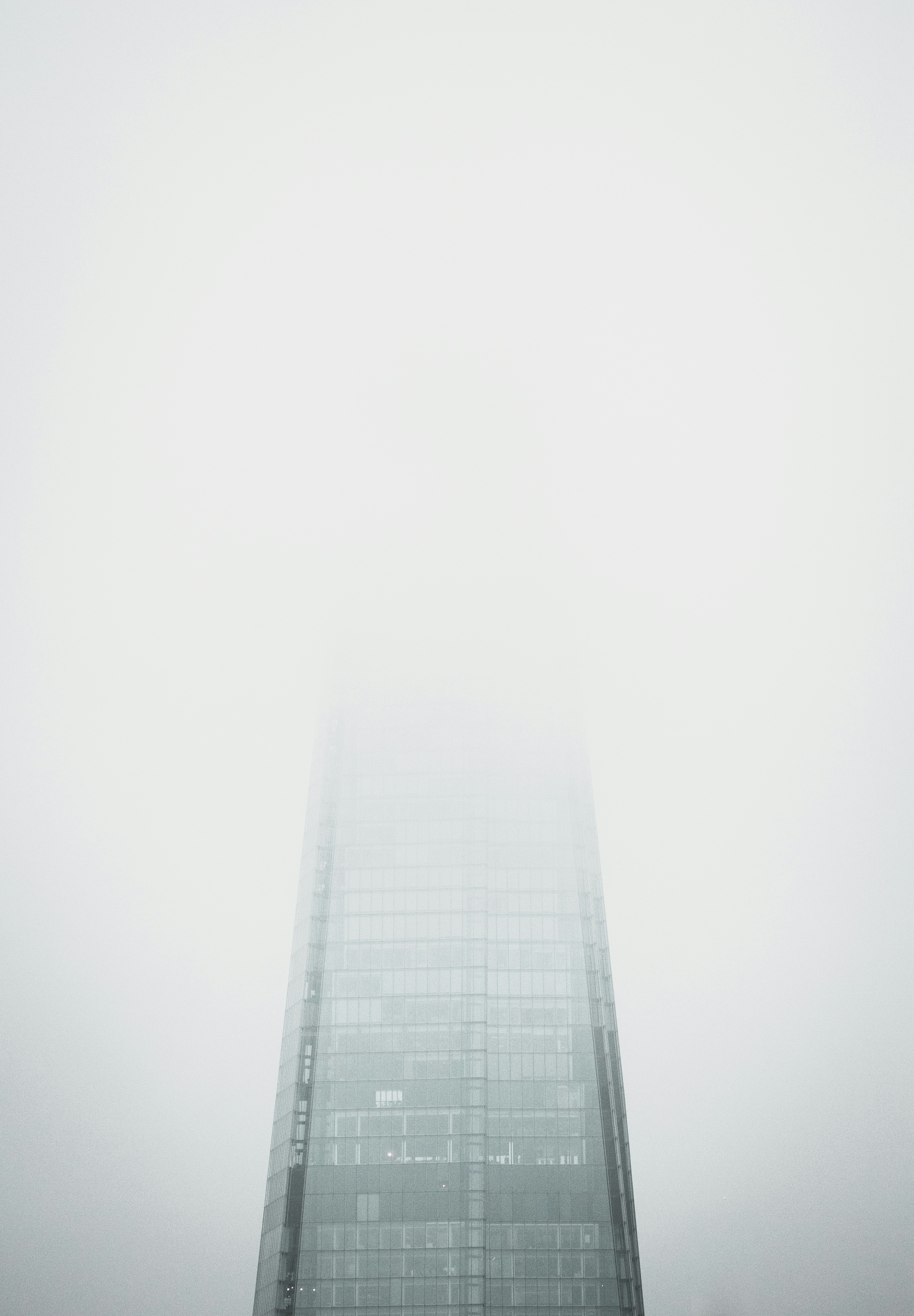A tall building in the middle of a foggy sky photo – Free Grey Image on ...