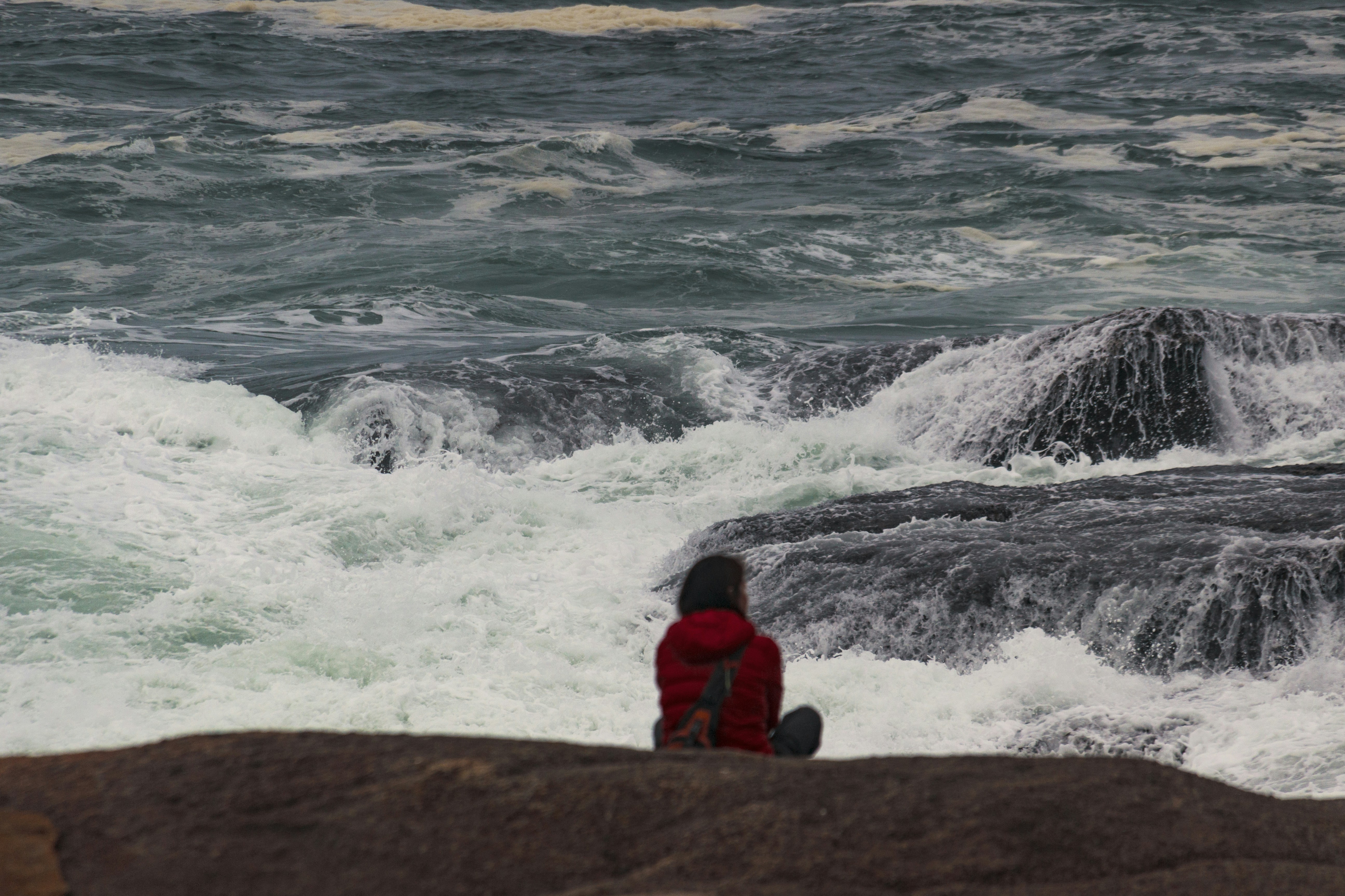Foto de persona sentada en la roca mirando el mar foto – Imagen de ...