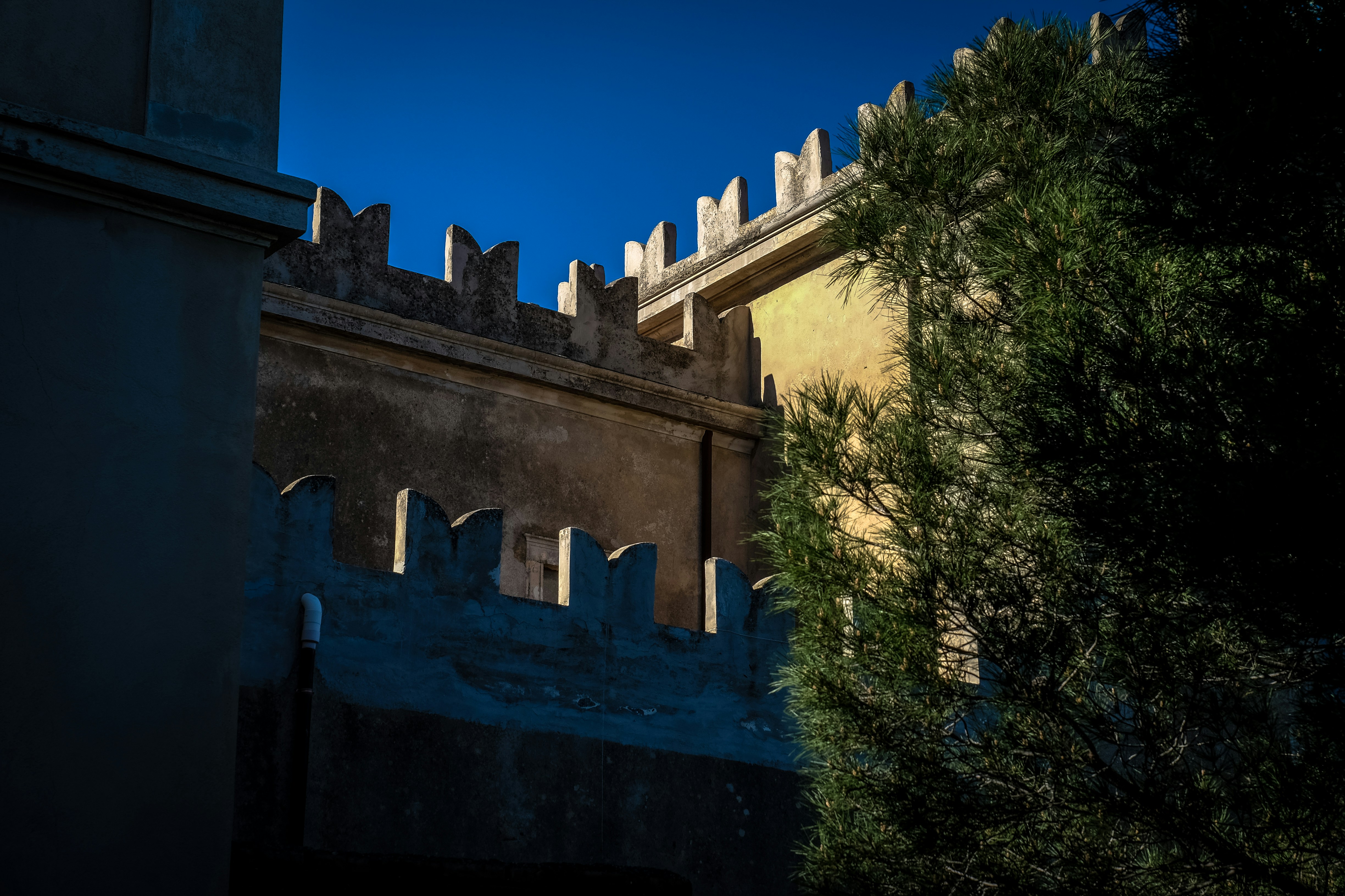 Shade and Stone: A fortress wall under a blue midday sky