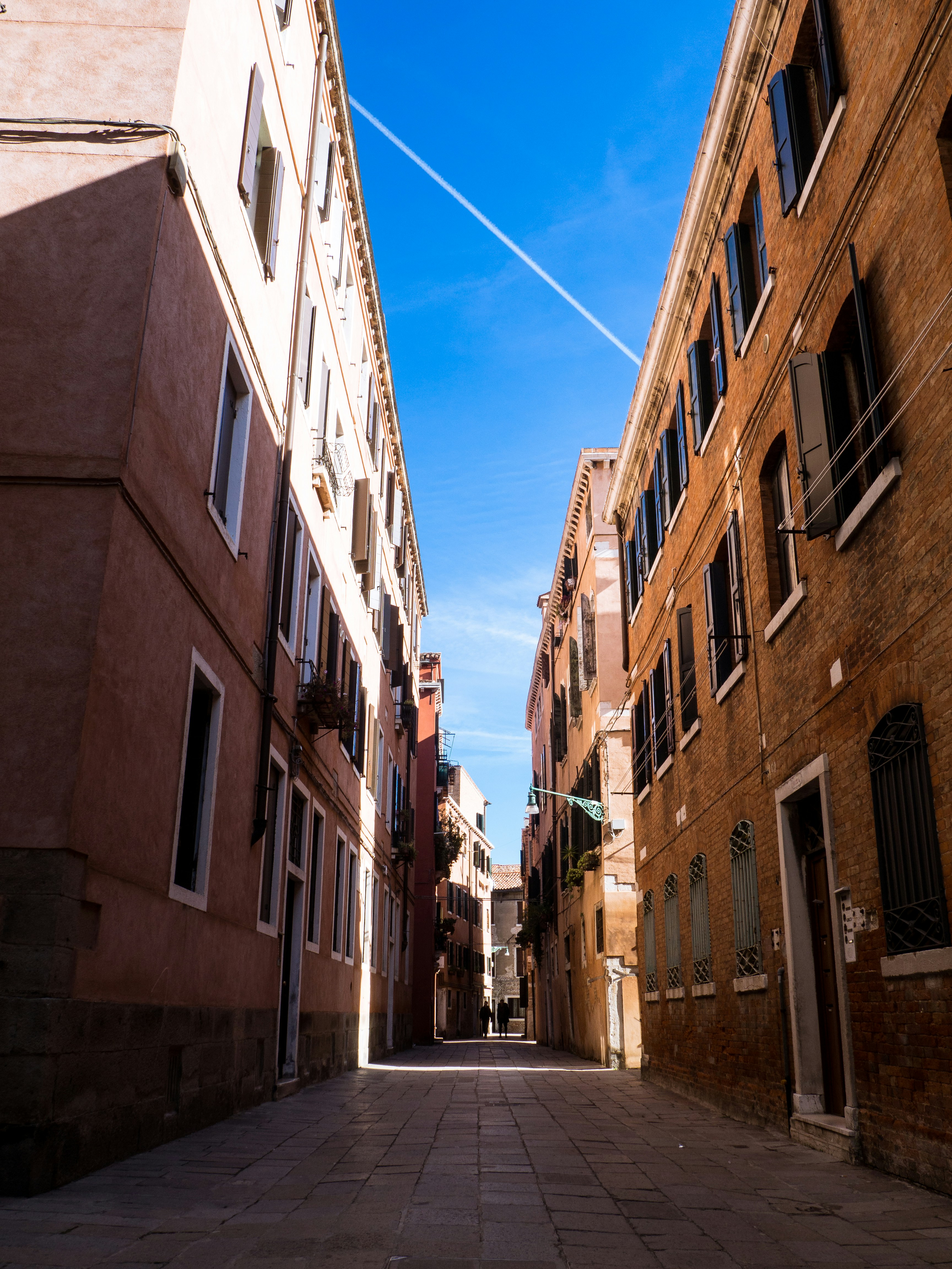 Narrows in venice | low angle photo of runway surrounded with brown concrete buildings under blue sky at daytime
