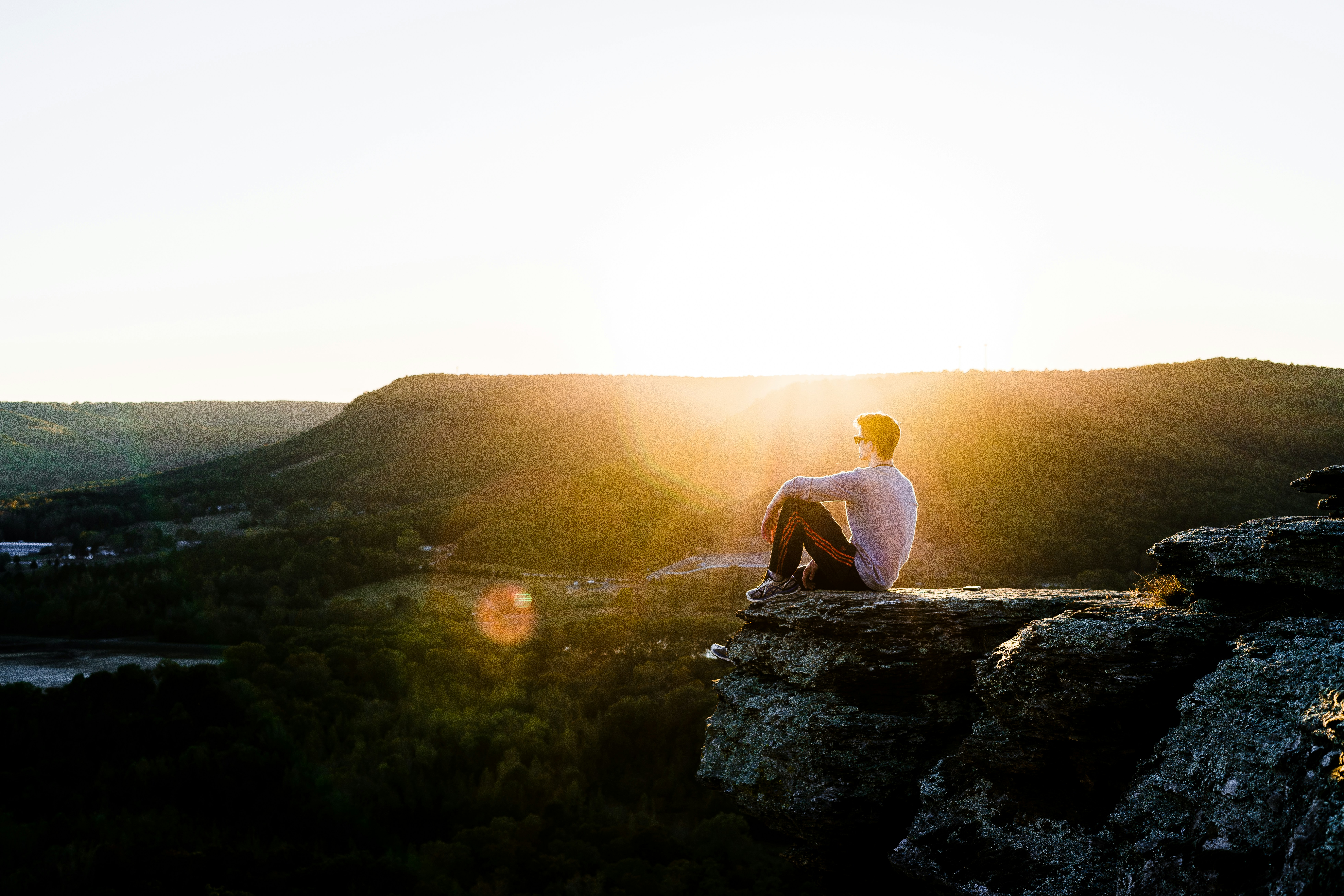 Man sitting on rock near cliff with overlooking mountains photo – Free ...