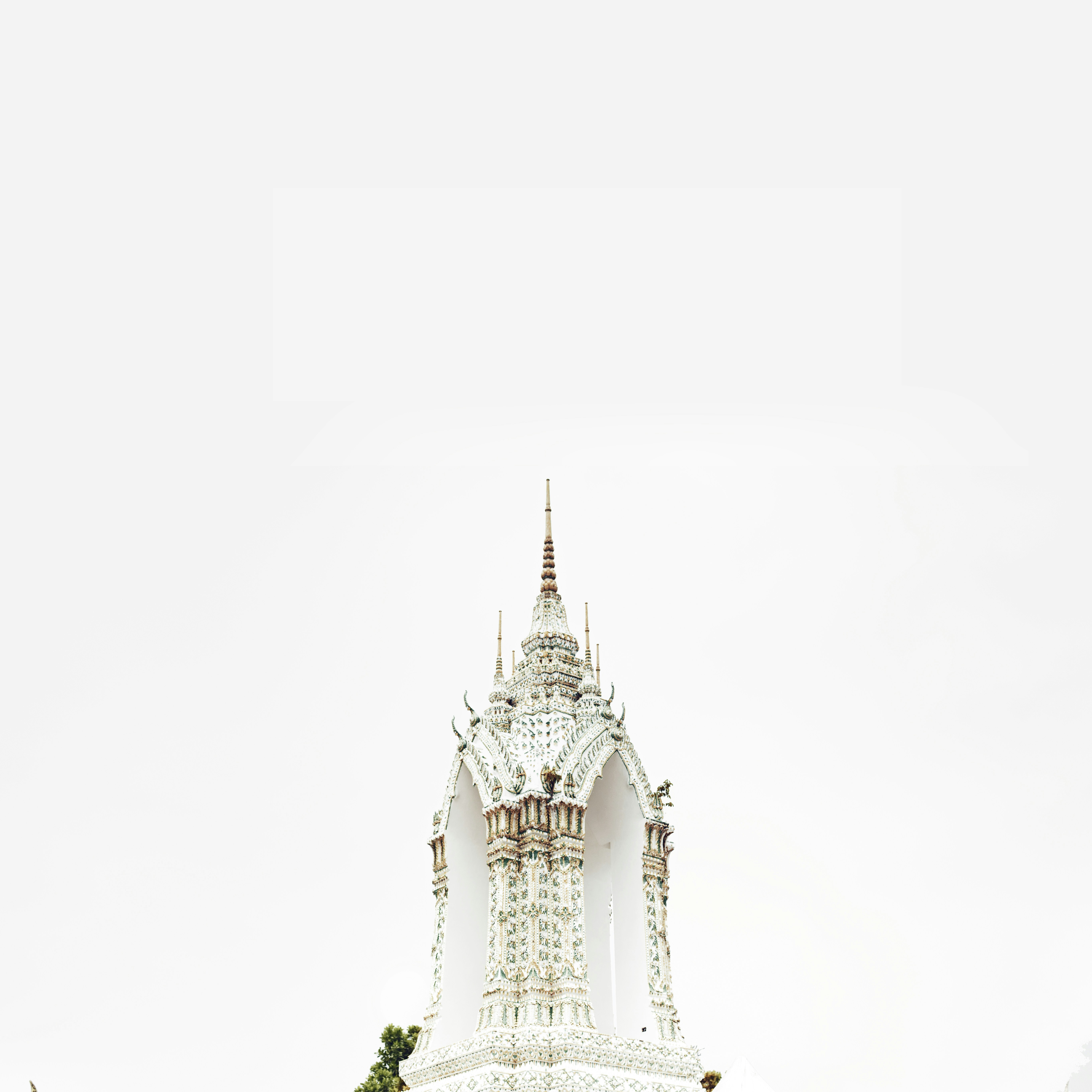 Intricate white temple spire rises gracefully against a minimalistic background, showcasing ornate architectural details. The design reflects cultural artistry and tranquility.