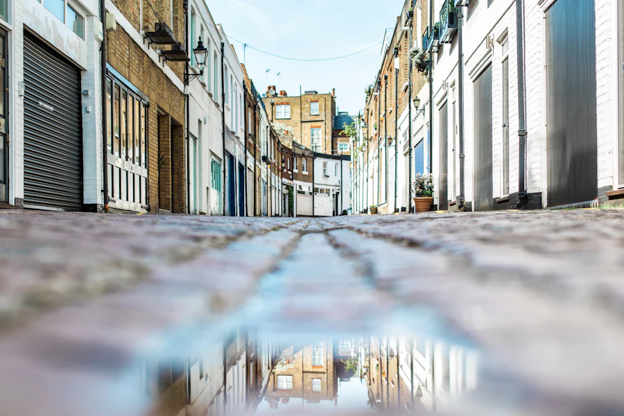 Cobblestone alleyway reflecting buildings in puddles after rain, showcasing urban architecture and tranquility.
