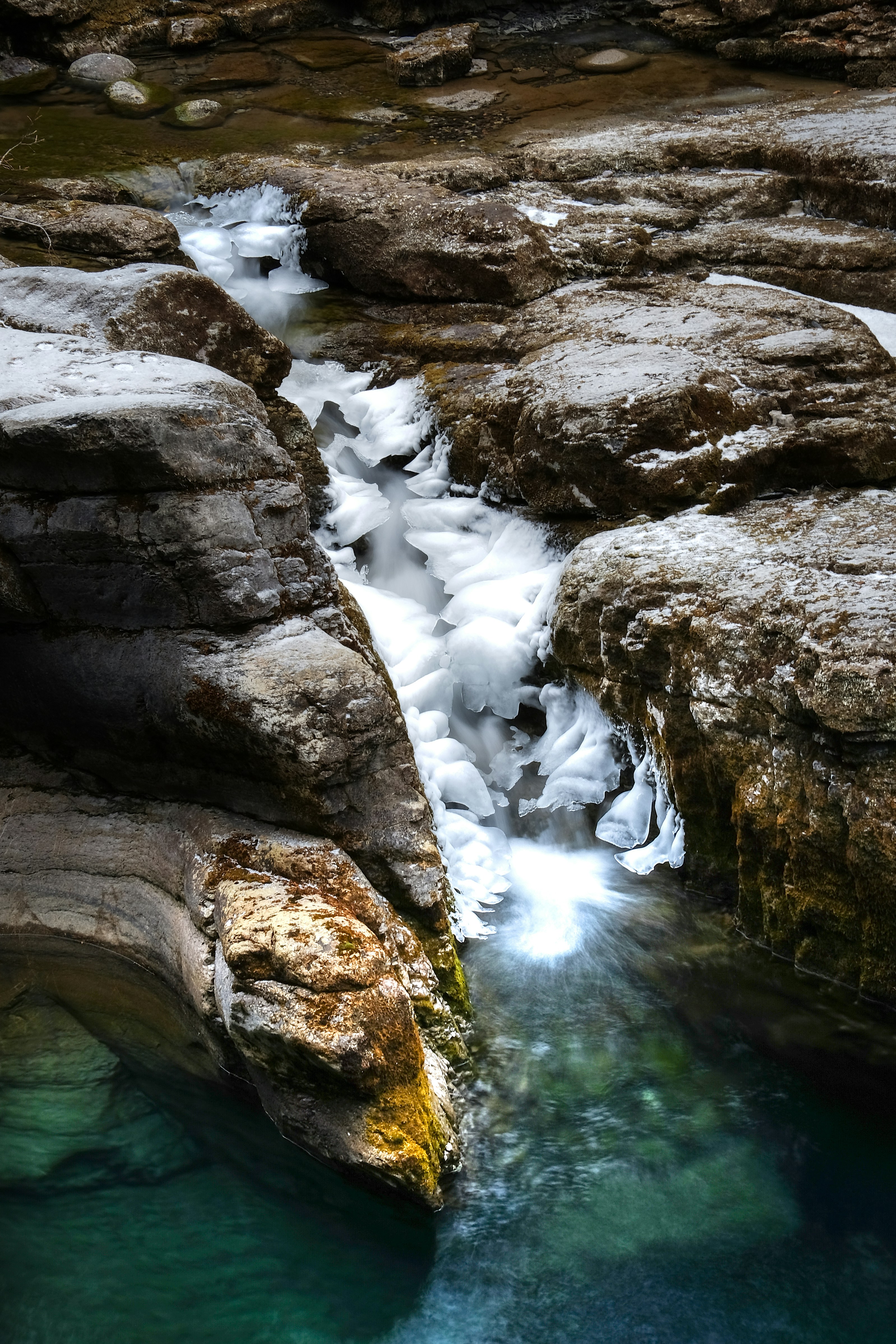 Ice-veined channel carved through basalt: a frozen waterfall of blue-green depths