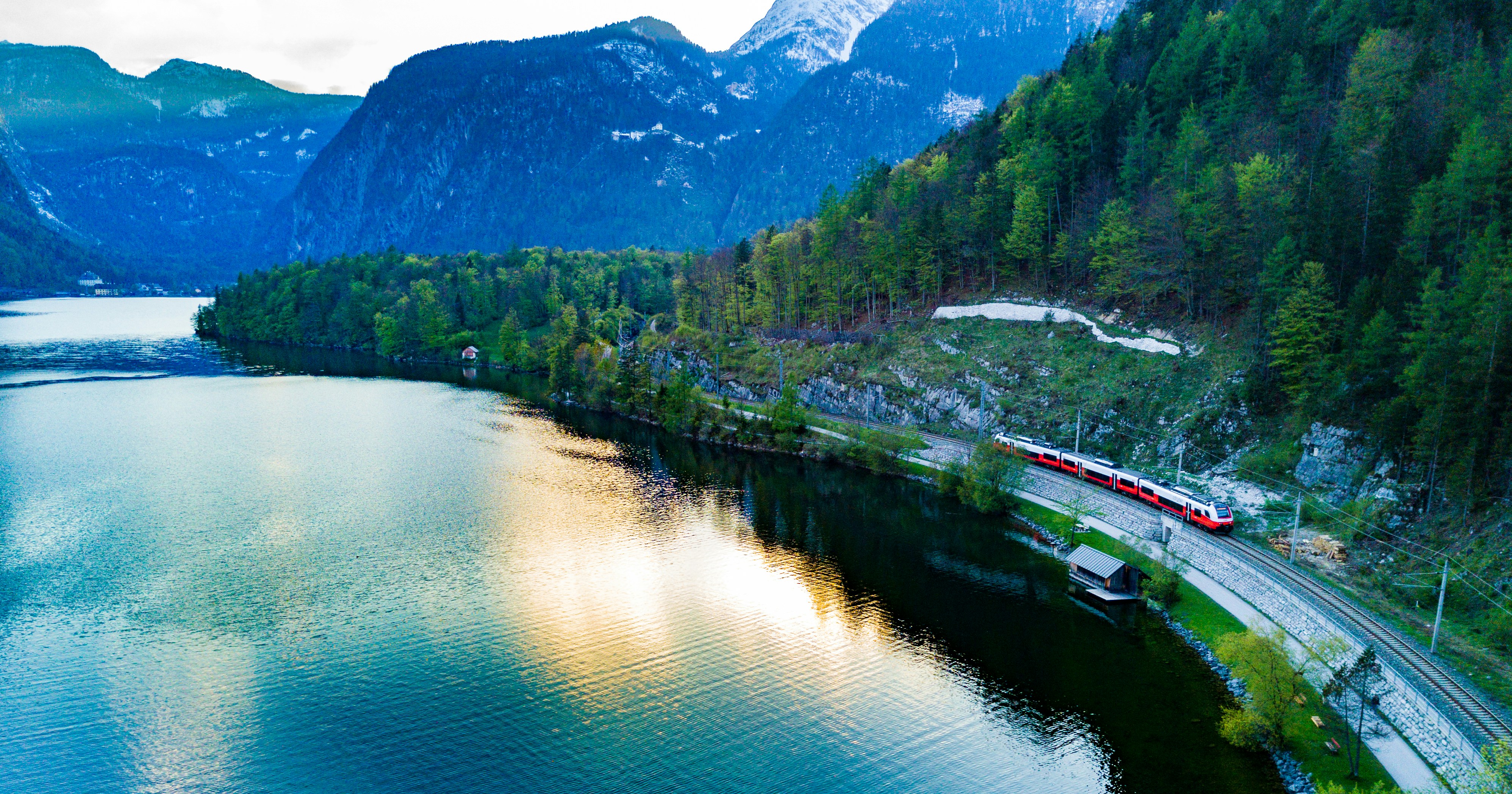 Red Train Tracing a Winding Fjord Along a Glassy Alpine Lake