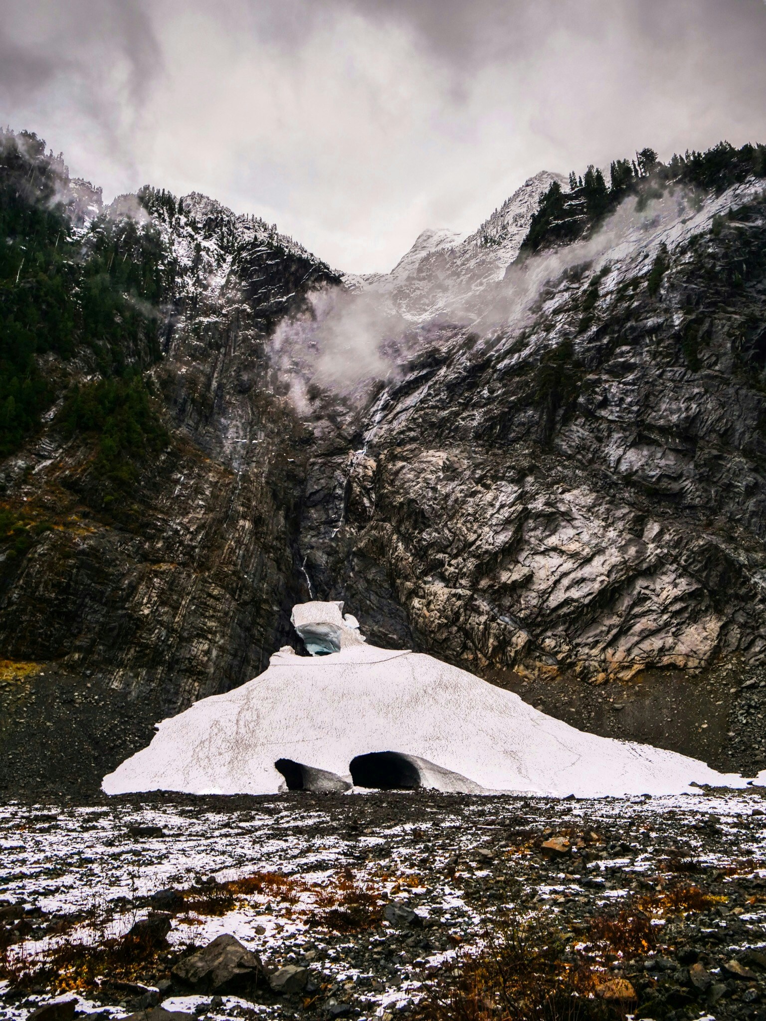 Glacial Gateway: Snow Bridge Beneath Towering, Misty Cliffs