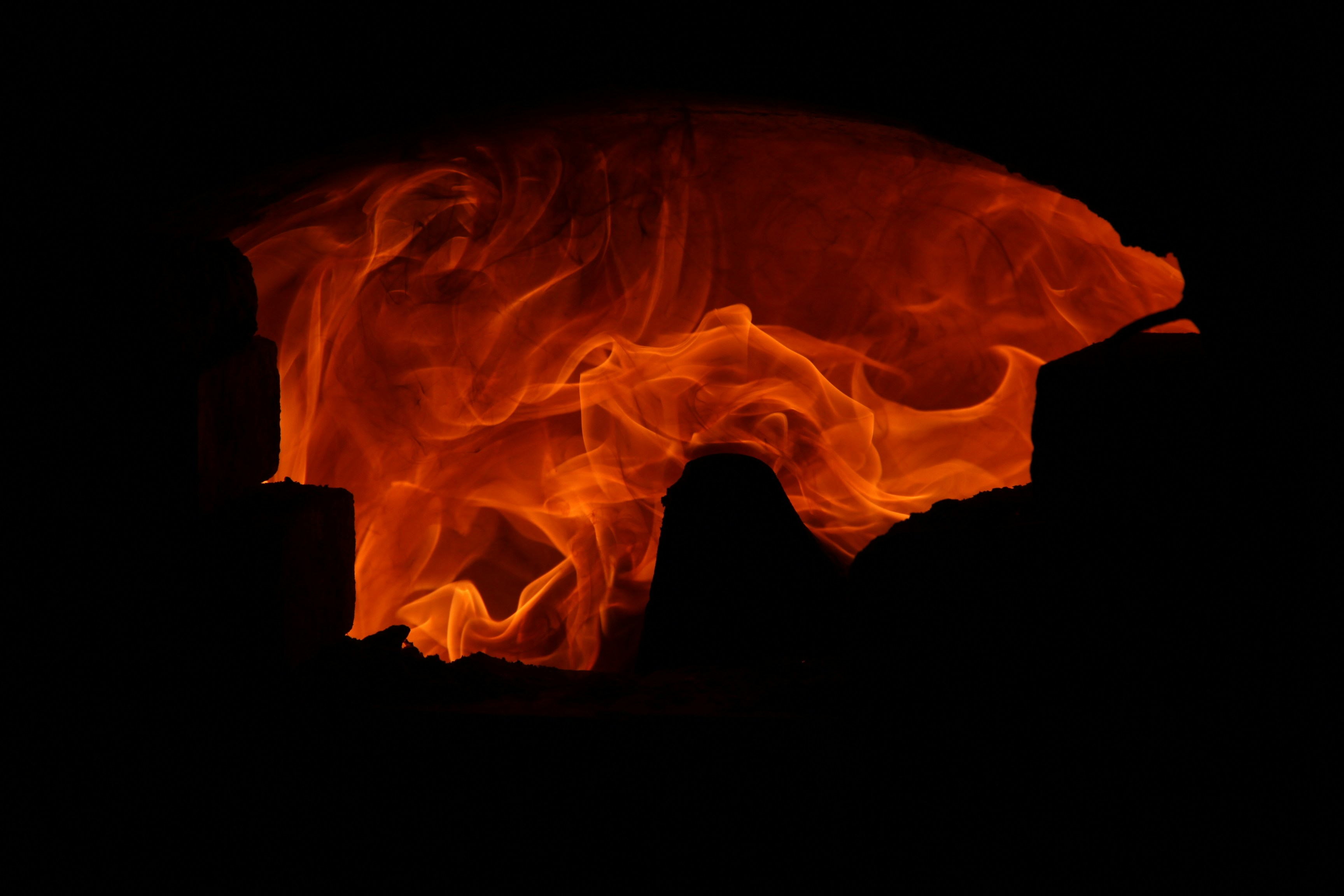 Swirling flames dance within a darkened furnace, casting a warm orange glow.