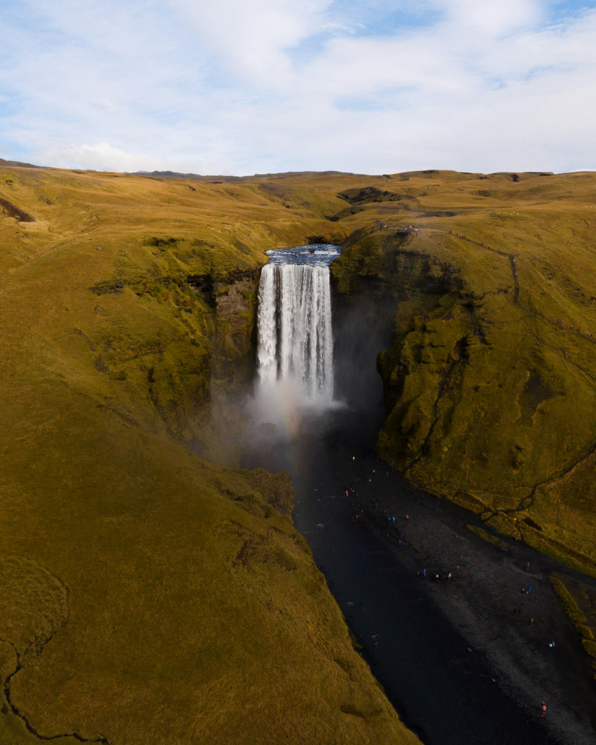 Vertical Curtain Over a Golden Canyon: A Drone View of a Misty Falls