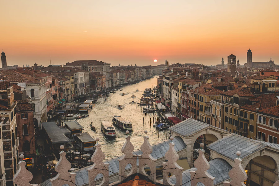 Sunrise over Venice's Grand Canal with boats navigating between historic buildings.