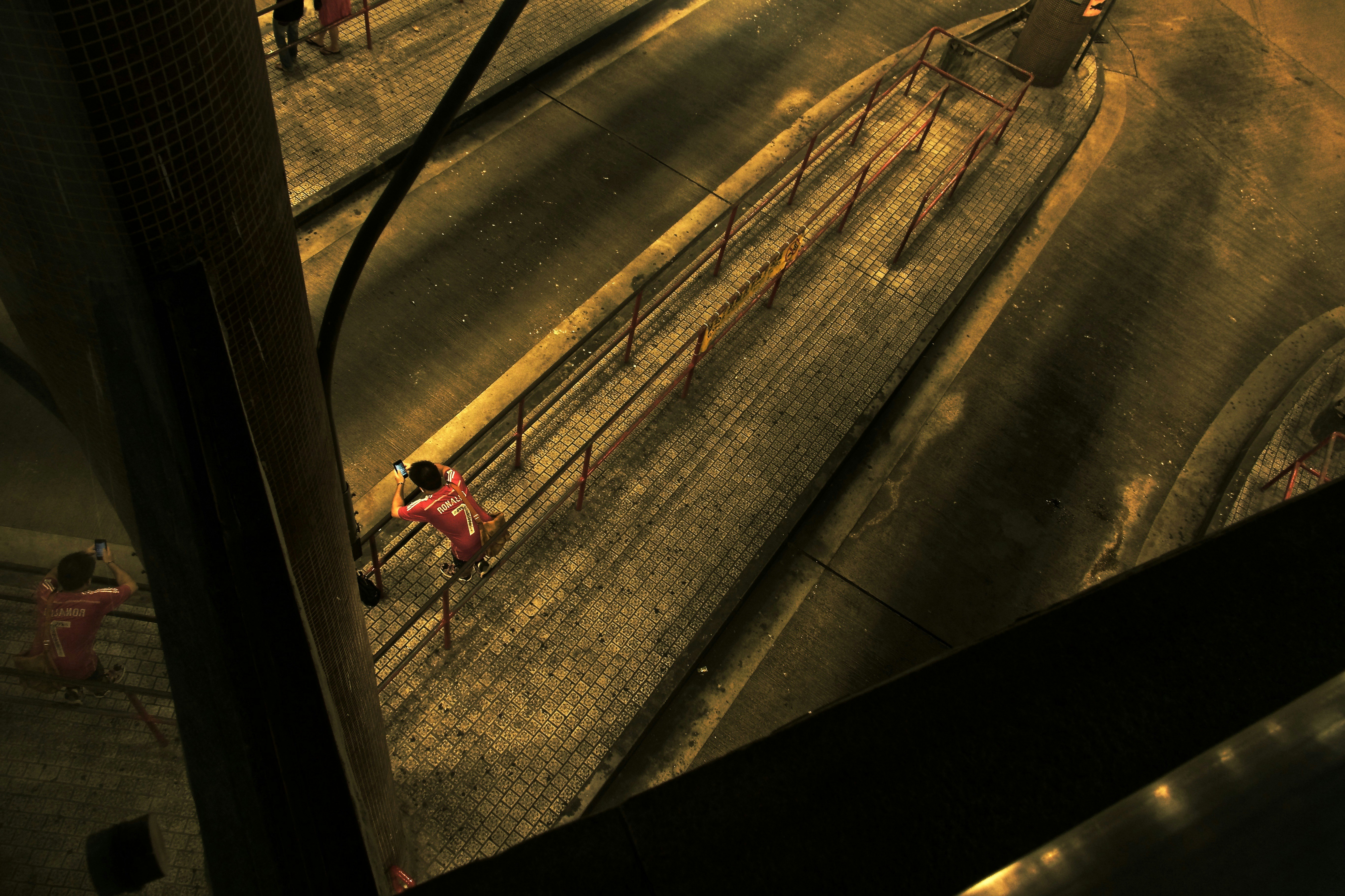 Amber-lit descent: a solitary figure clings to the railing beneath exposed steel beams