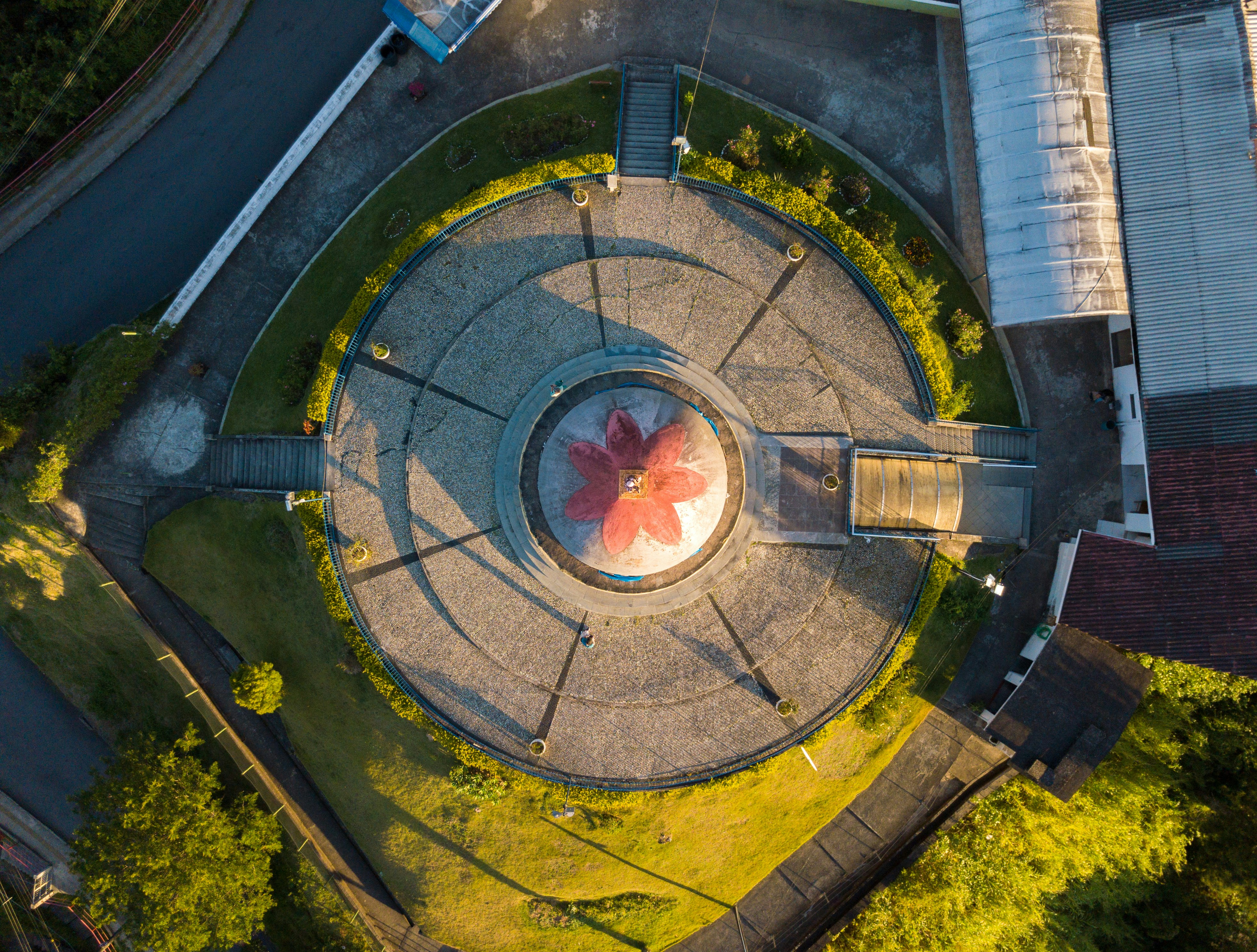 Aerial view of a circular floral design surrounded by pathways and greenery, showcasing architectural symmetry and natural beauty.