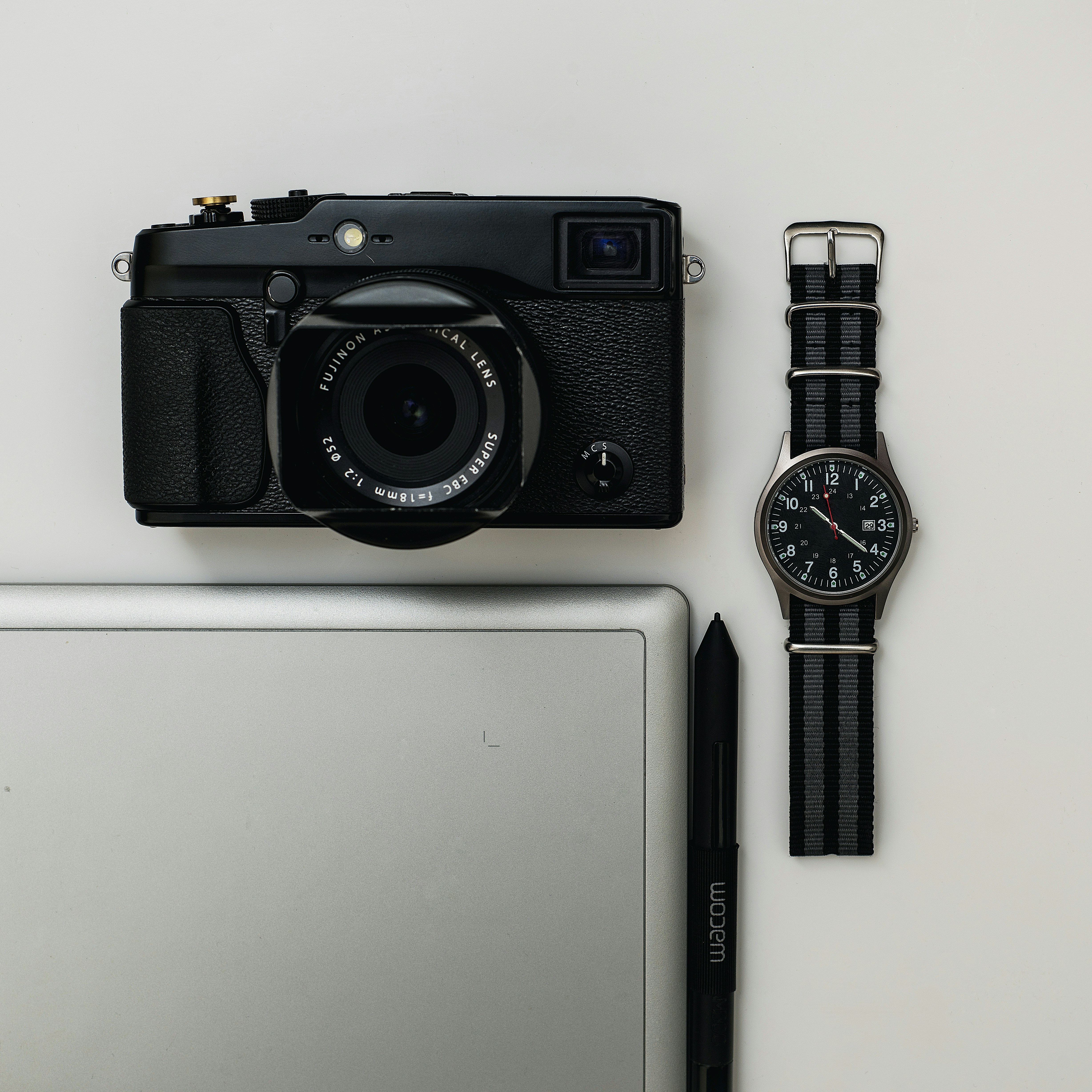 Black point-and-shoot camera and round black analog watch with fabric ...