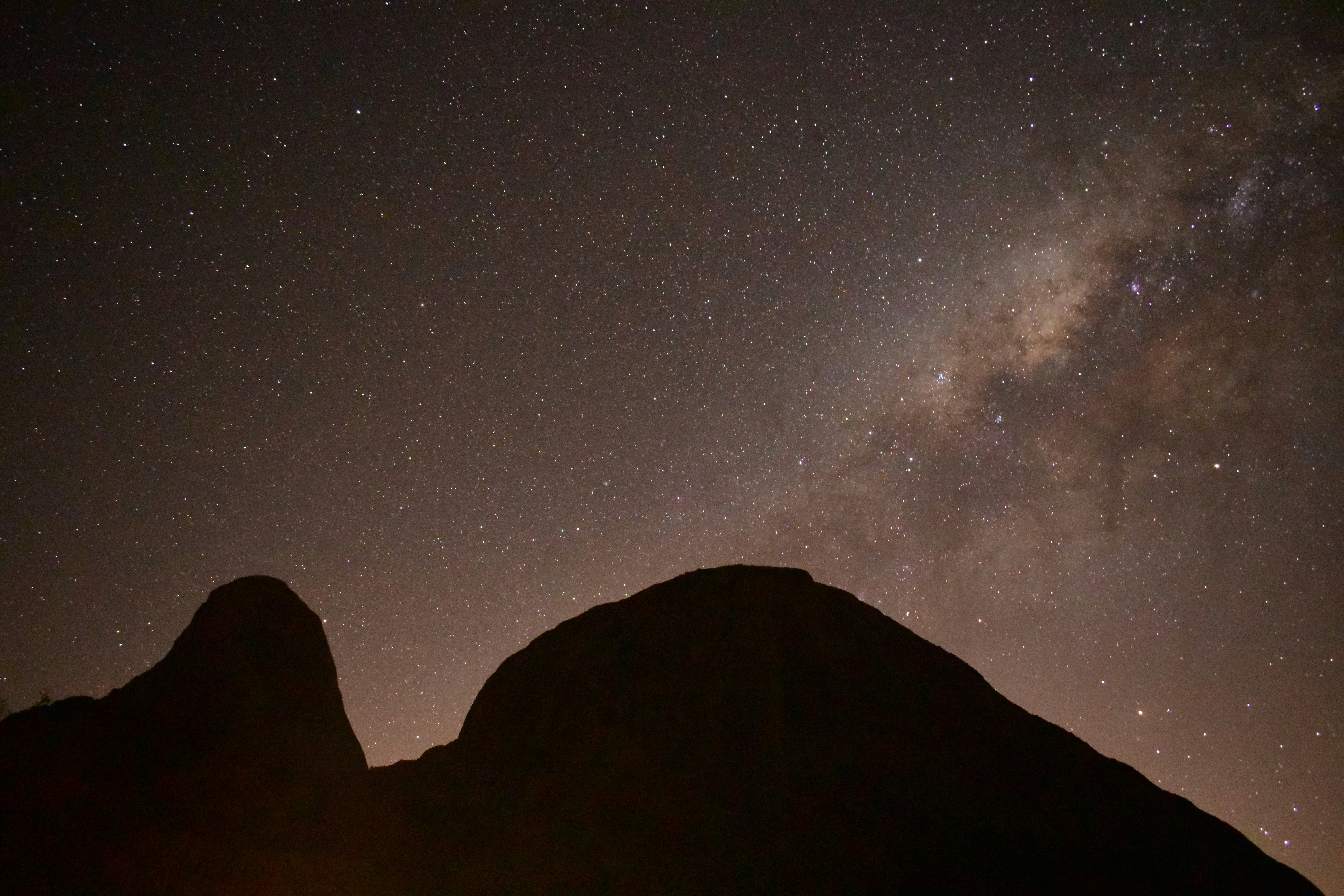 Silhouetted rocky peaks beneath a star-filled night sky with the Milky Way visible.