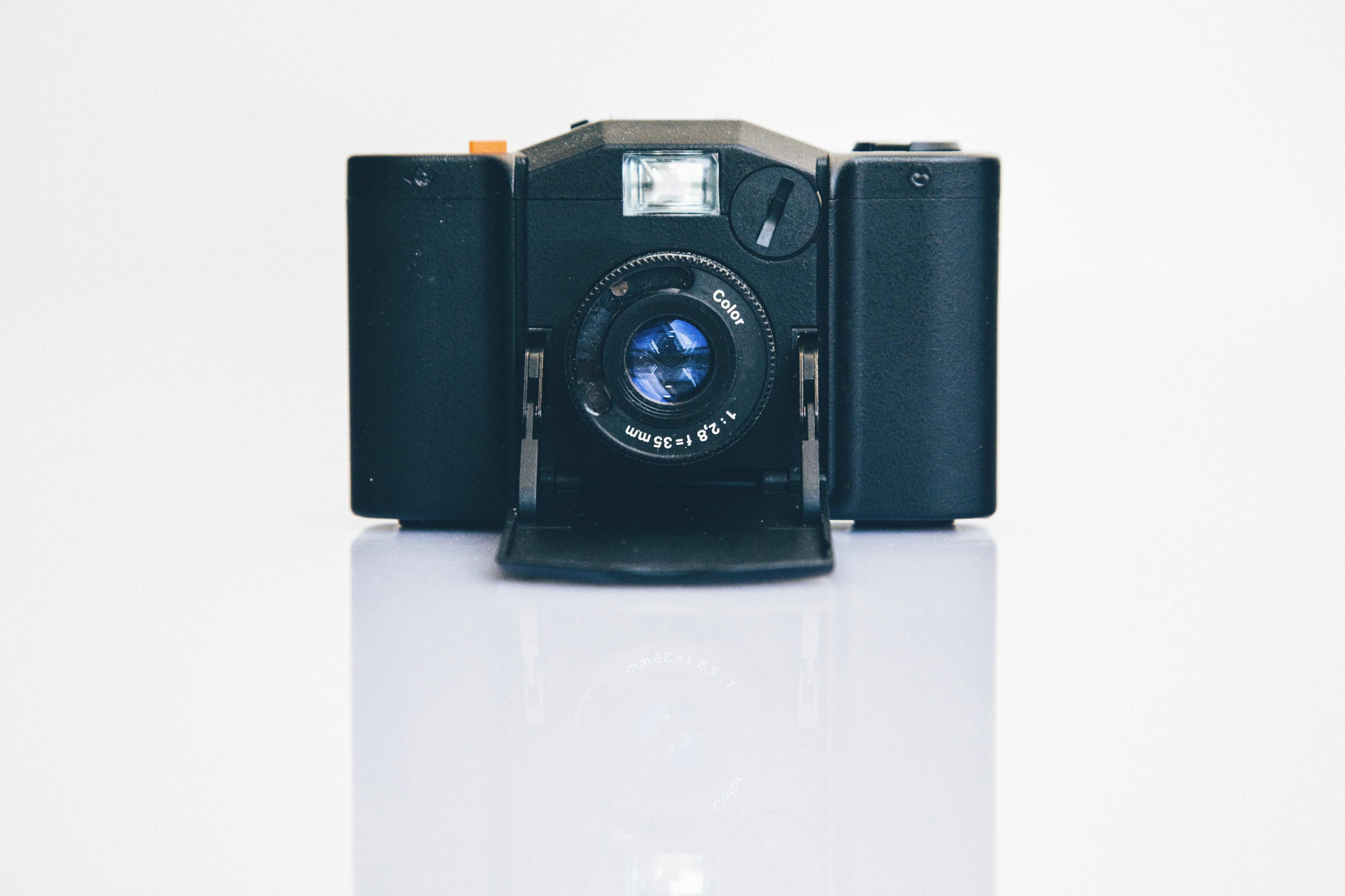 Front view of a vintage camera with a reflective surface creating a subtle mirror effect.