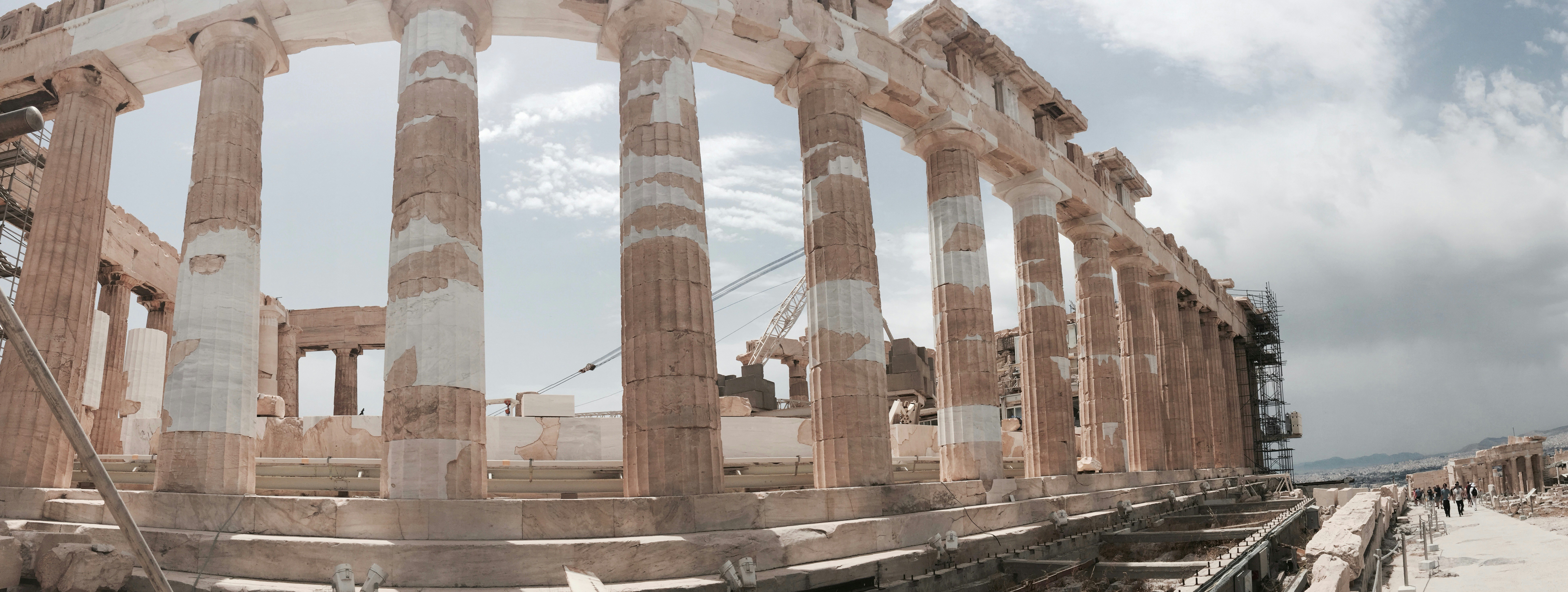 Parthenon columns standing tall against a partly cloudy sky with restoration work visible.