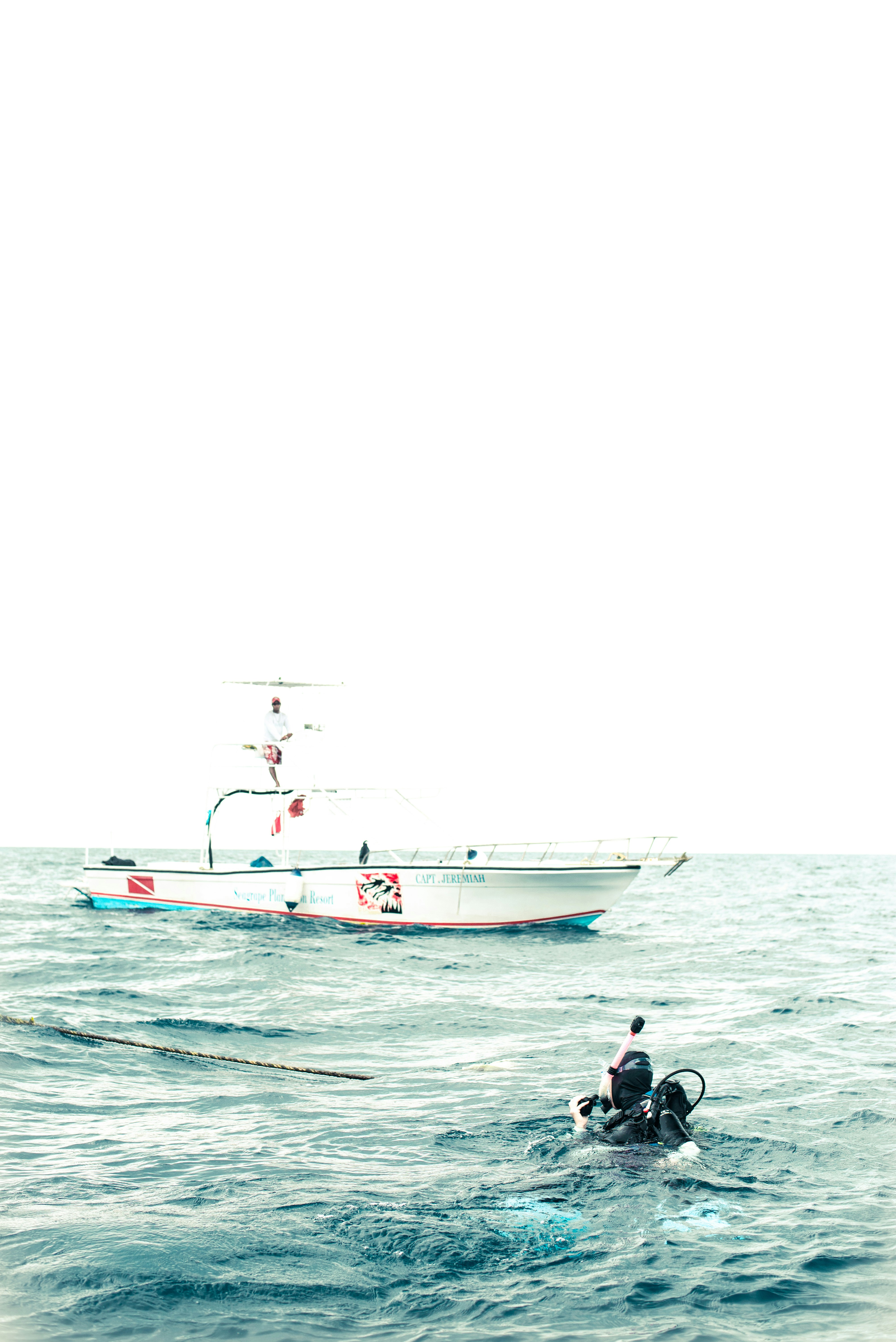 A diver emerges from the depths of the ocean, while a boat waits nearby, ready to assist. The scene captures the essence of underwater exploration.