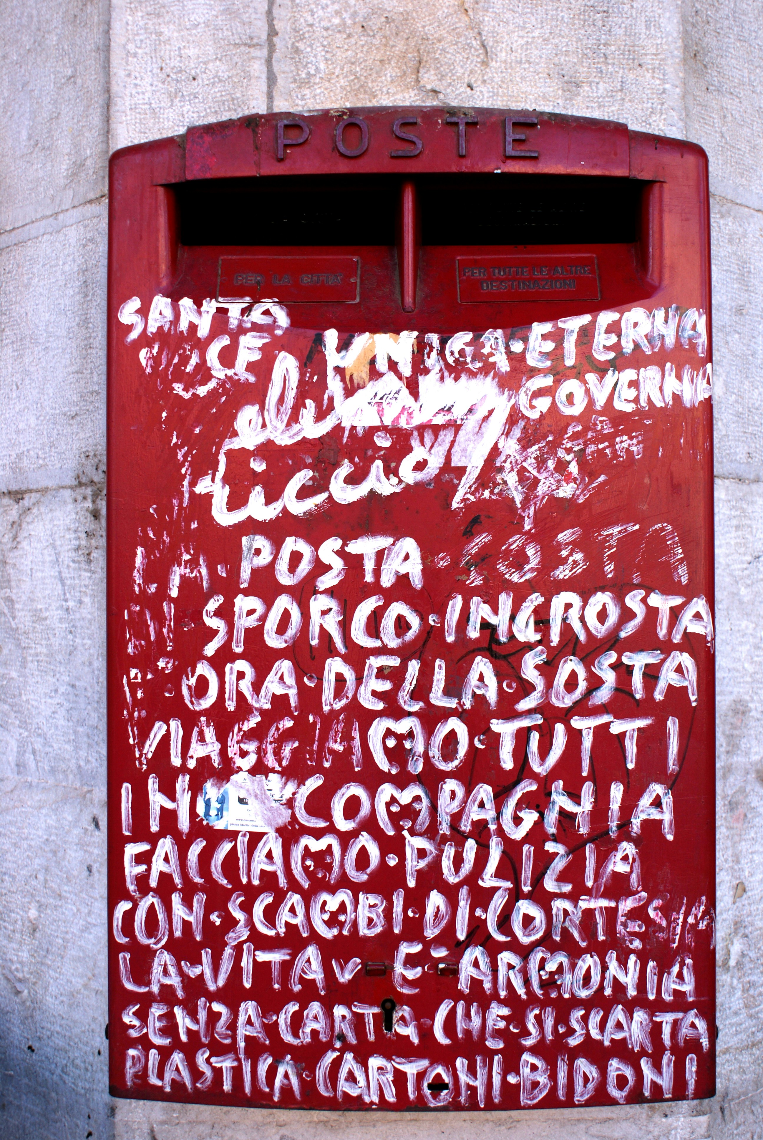 A weathered red mailbox adorned with faded, handwritten messages reflecting community sentiments and calls for action.