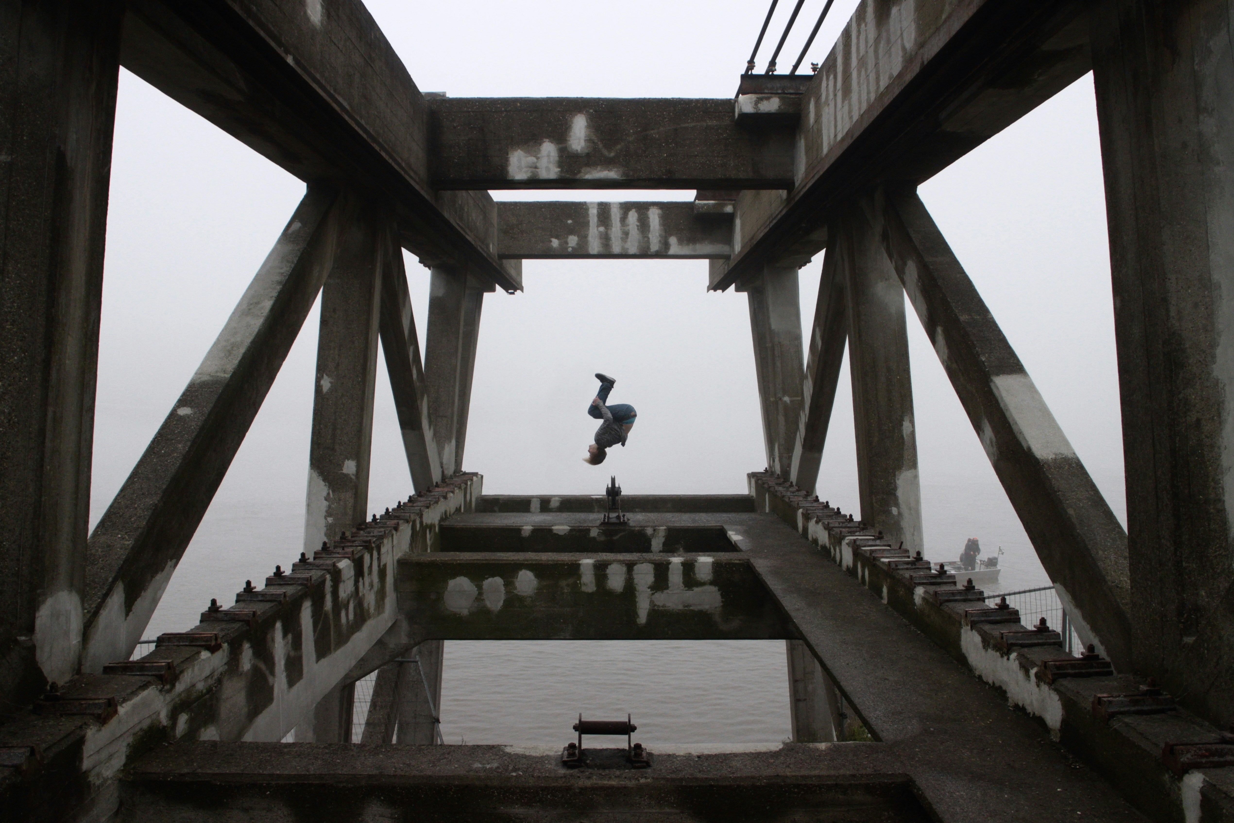 Cas de Klerk, Dutch young freerunner doing a backflip in the cold fog on a dangerous construction. | person doing back flip on building edge during daytime
