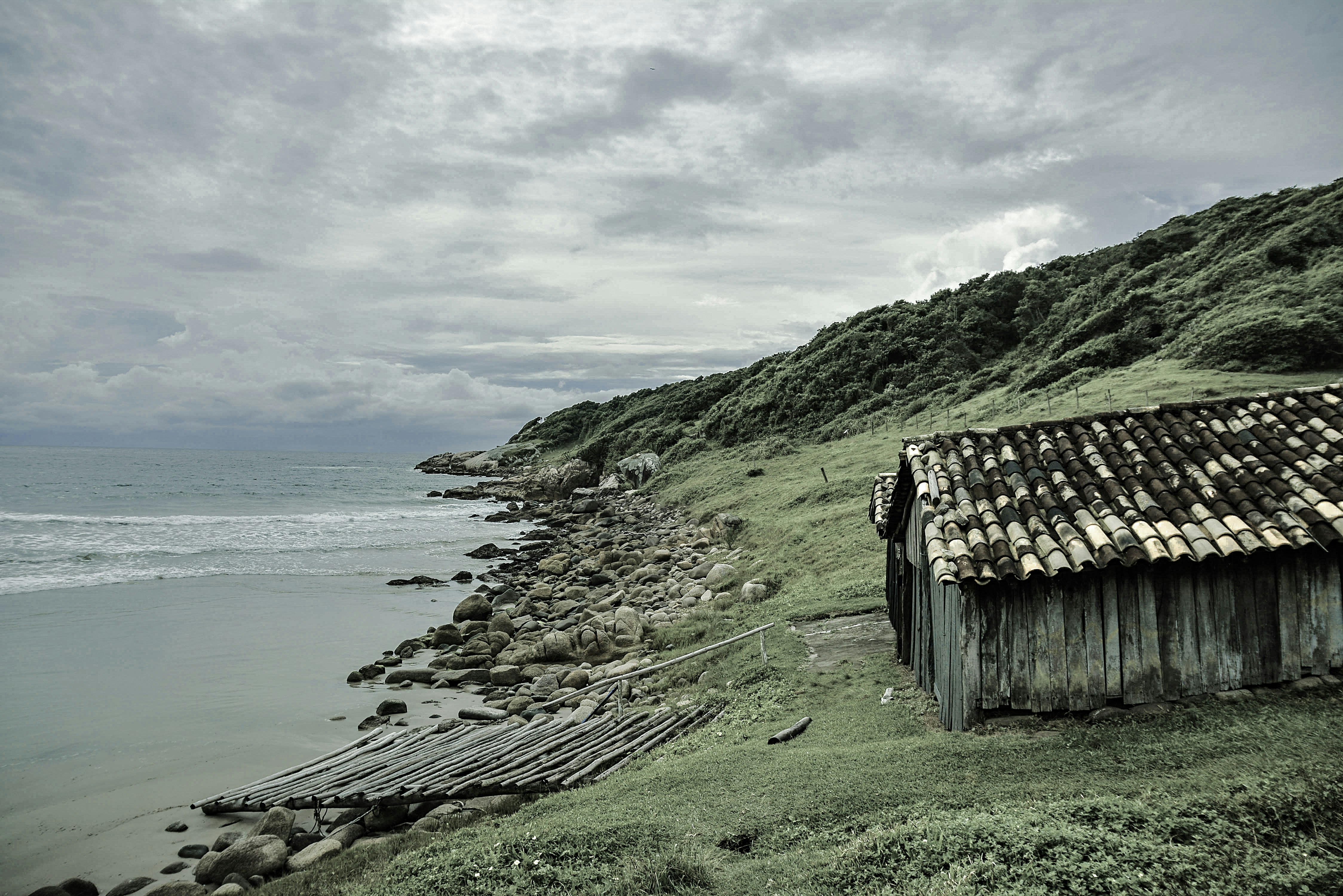 House beach | brown house beside ocean under cloudy sky during daytime