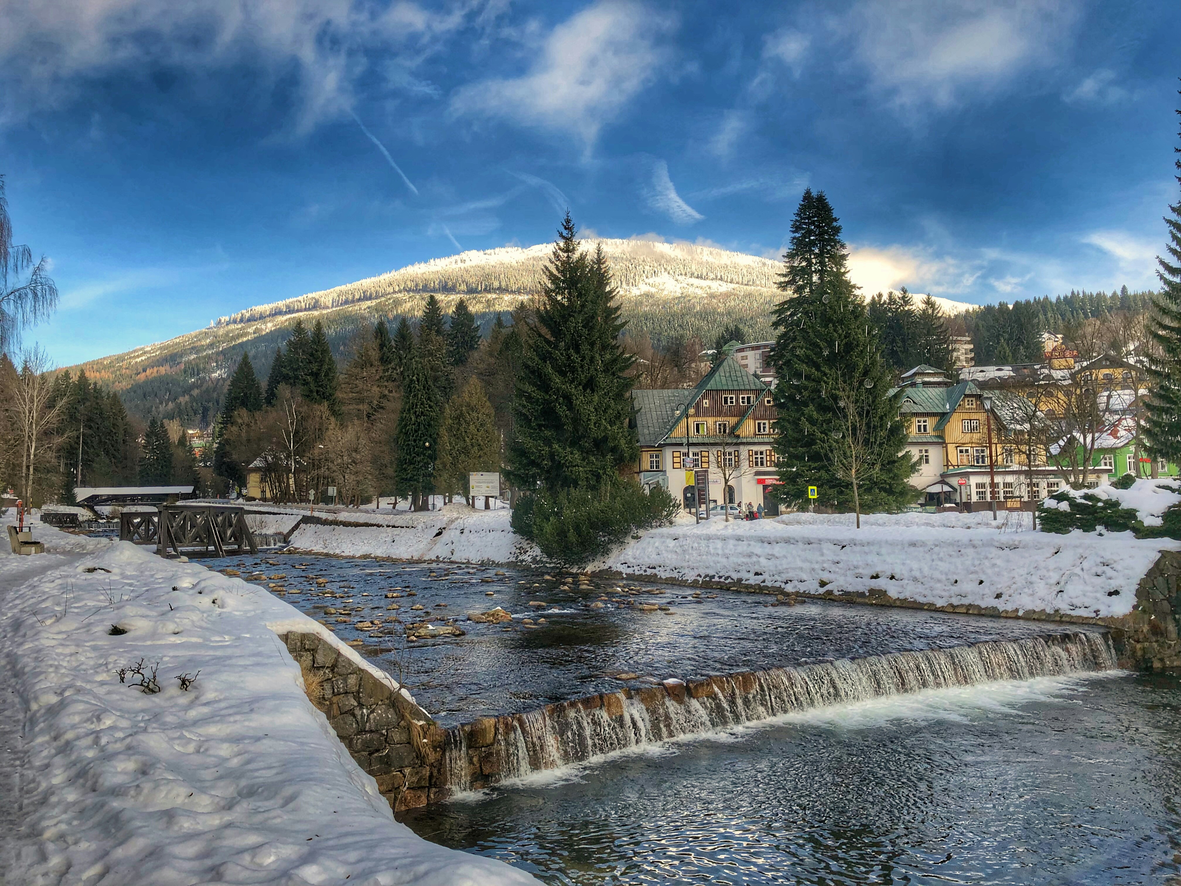Snowbound Village Beside a Cascading Stream Under a Blue-Tinted Sky