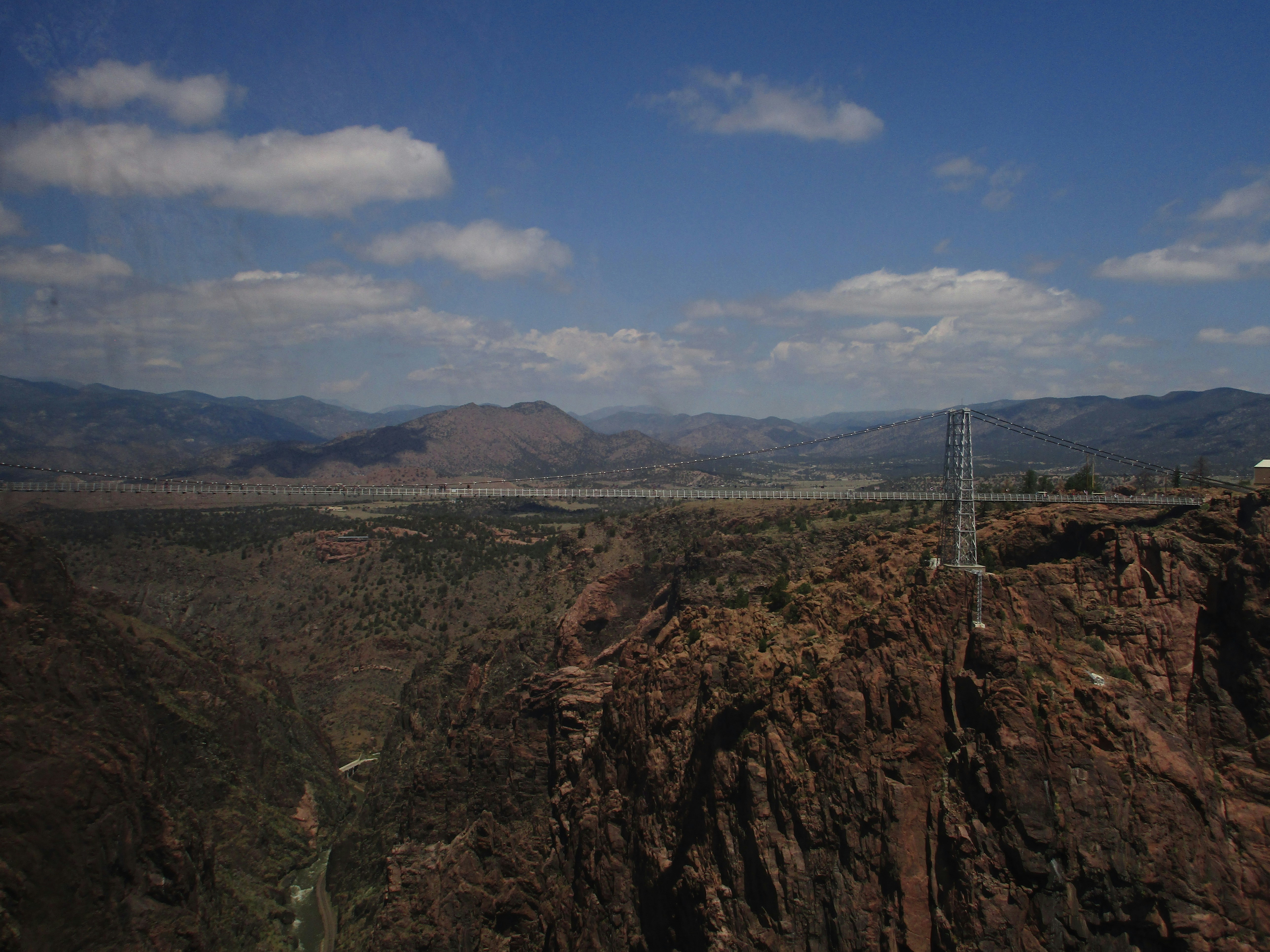 Long suspension bridge spans a deep canyon under a clear blue sky.