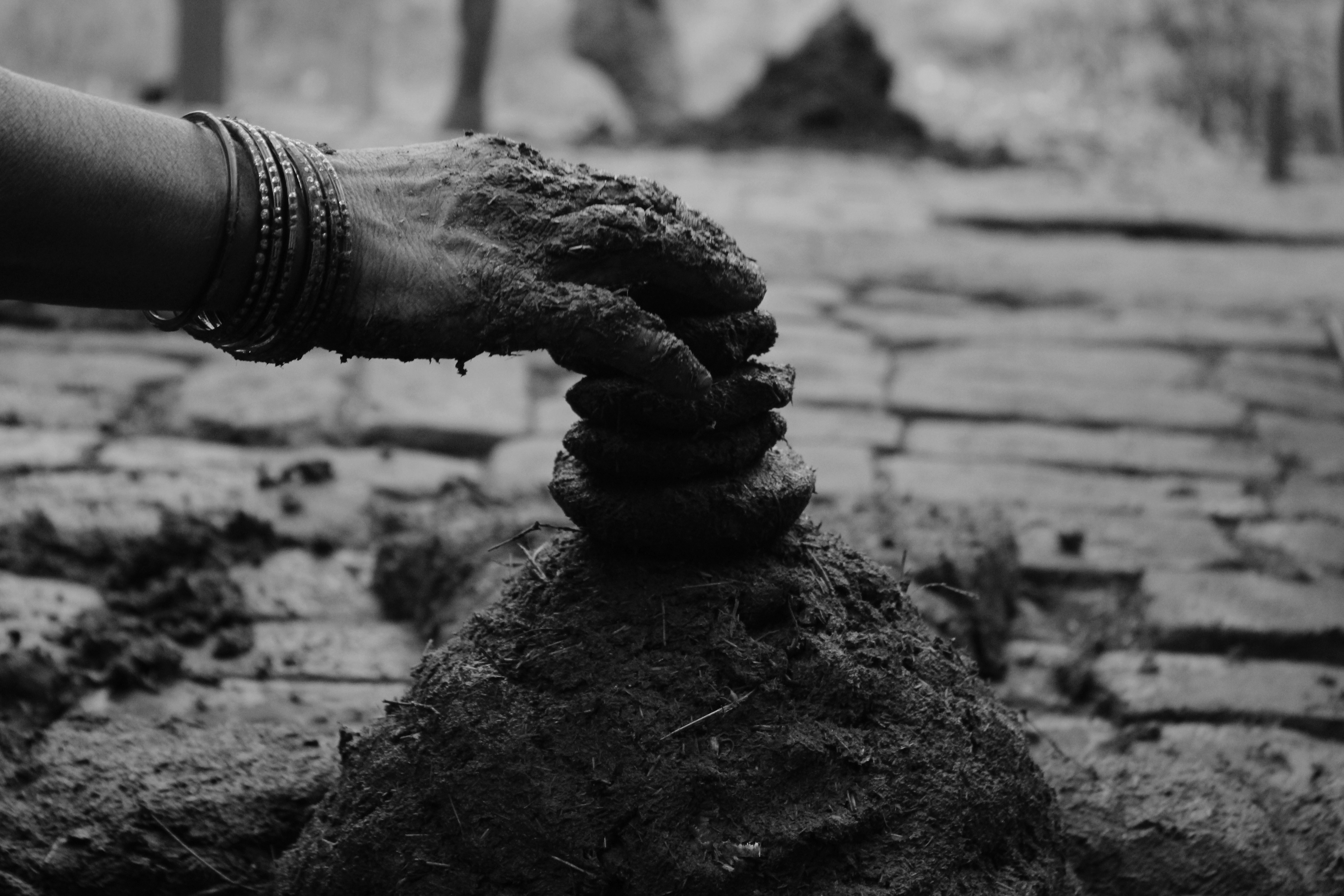 Stacking Ritual in Dust: A Hand Builds a Charred Miniature Tower