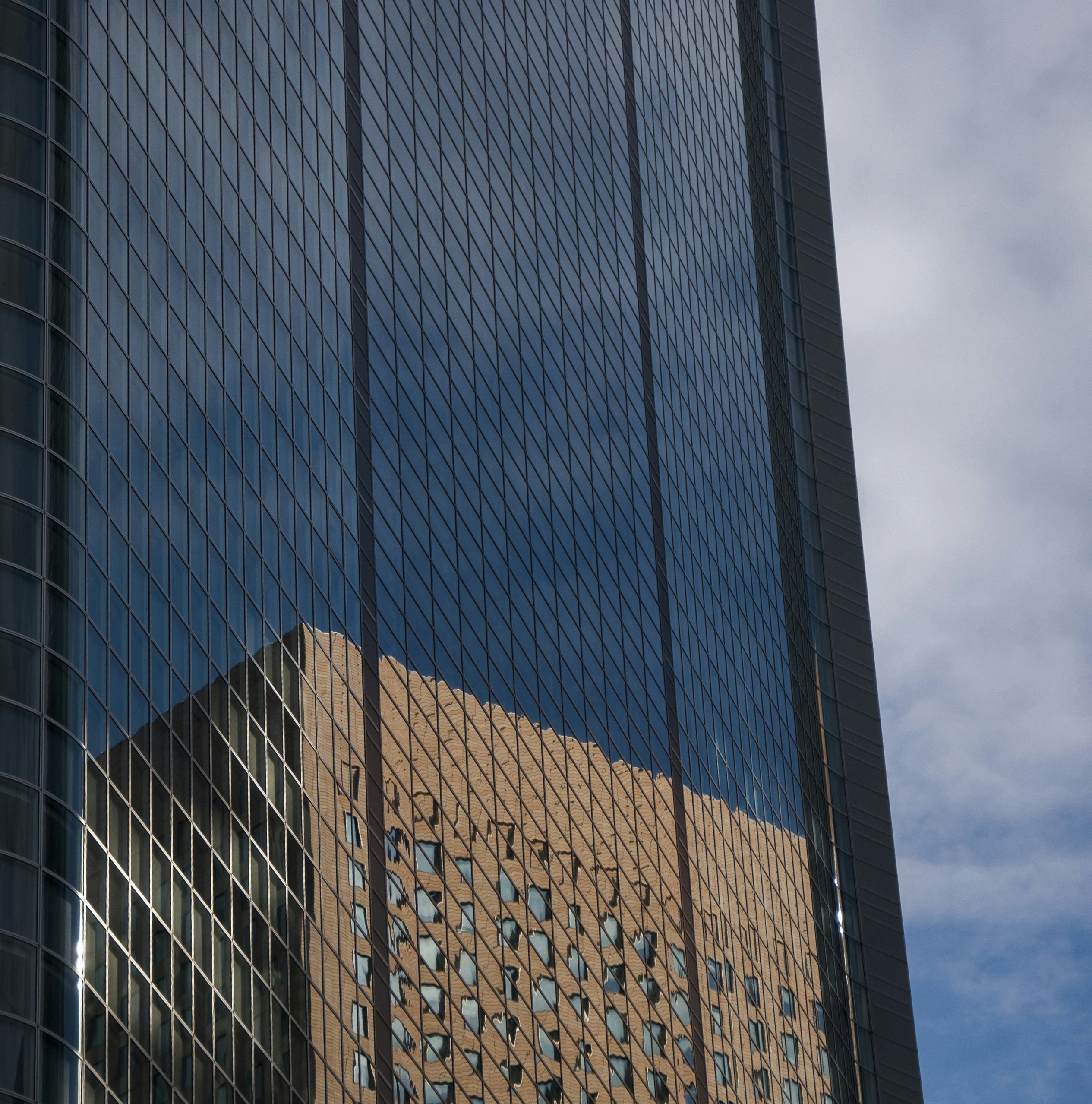 Reflective glass facade of a skyscraper showcasing the interplay of light and surrounding architecture.