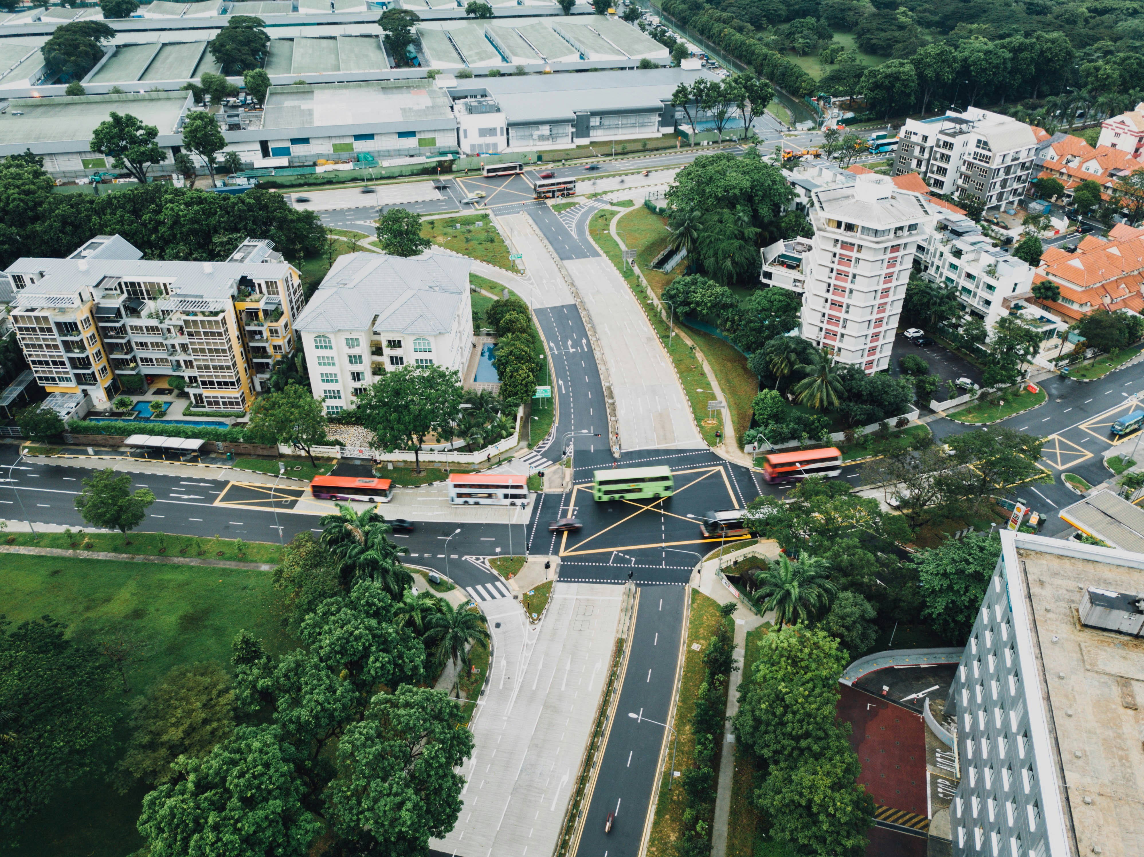 Aerial view of a complex urban intersection surrounded by greenery and residential buildings, showcasing traffic flow and city planning.