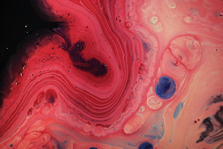 This experimental painting features swirls of pink, blue, black, and pale yellow paints. As the paints began to dry, I took this closeup.

The technique I use to create this kind of paint texture is called “fluid art,” and it relies on mixing a variety of mediums into acrylic paints to influence how they interact. I’ll use materials like glue, isopropyl alcohol, liquid silicone, and a butane torch. | a close up of a red and blue fluid substance