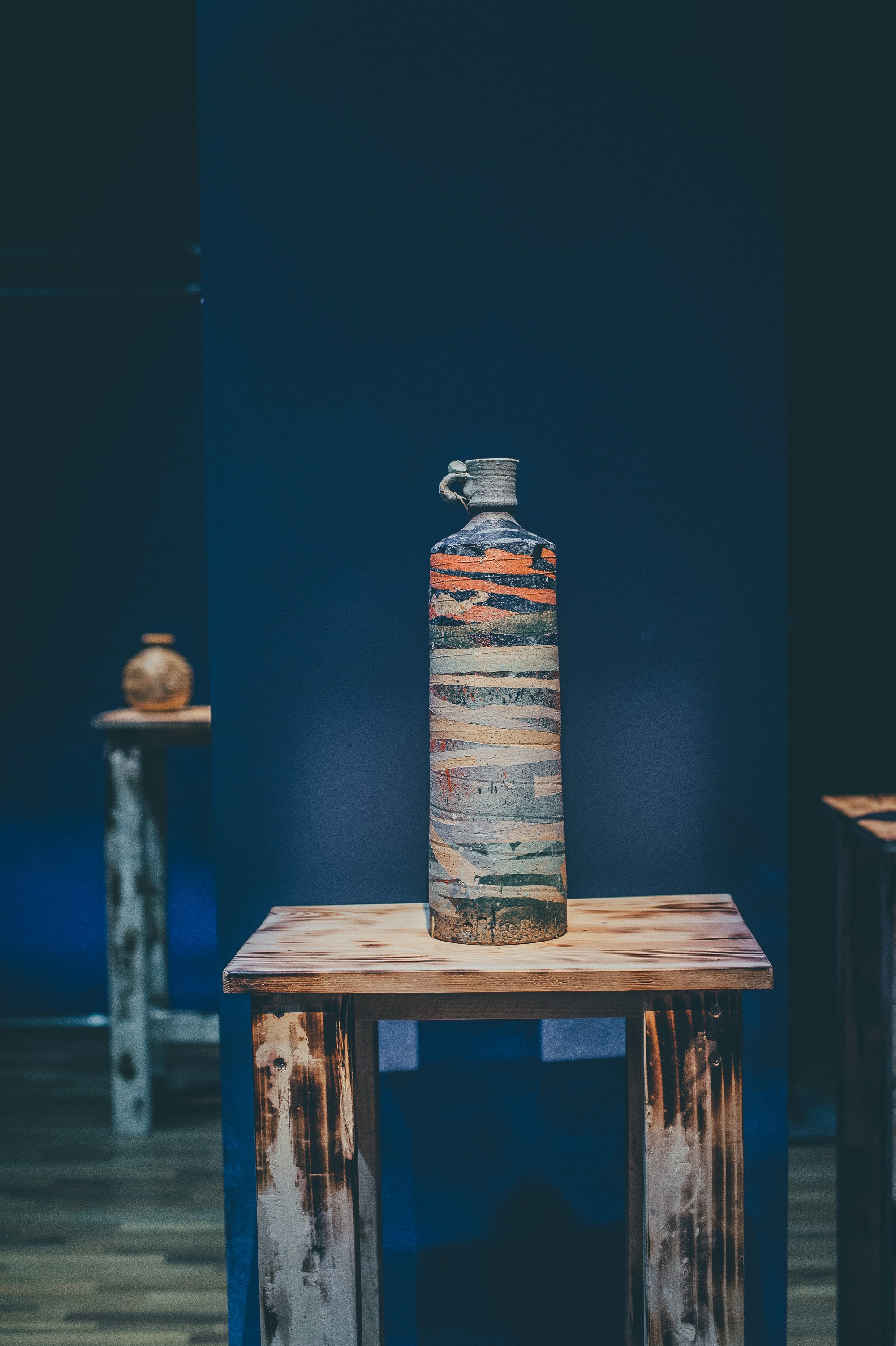Ceramic Vessel on a Weathered Pedestal in a Dim Gallery