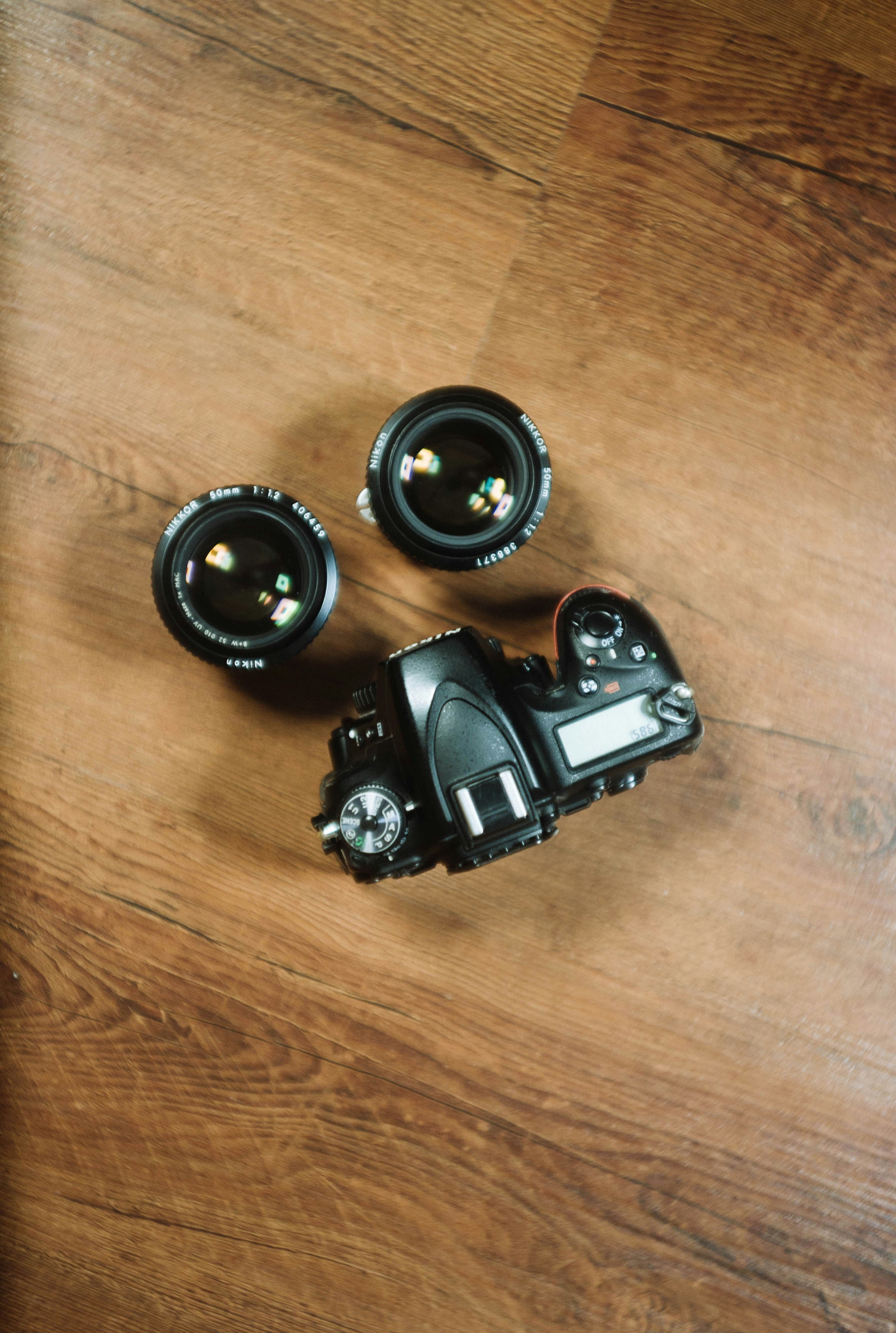 Leica M8 camera positioned on wooden surface with two interchangeable lenses nearby. Perfectly showcases essential photography gear.