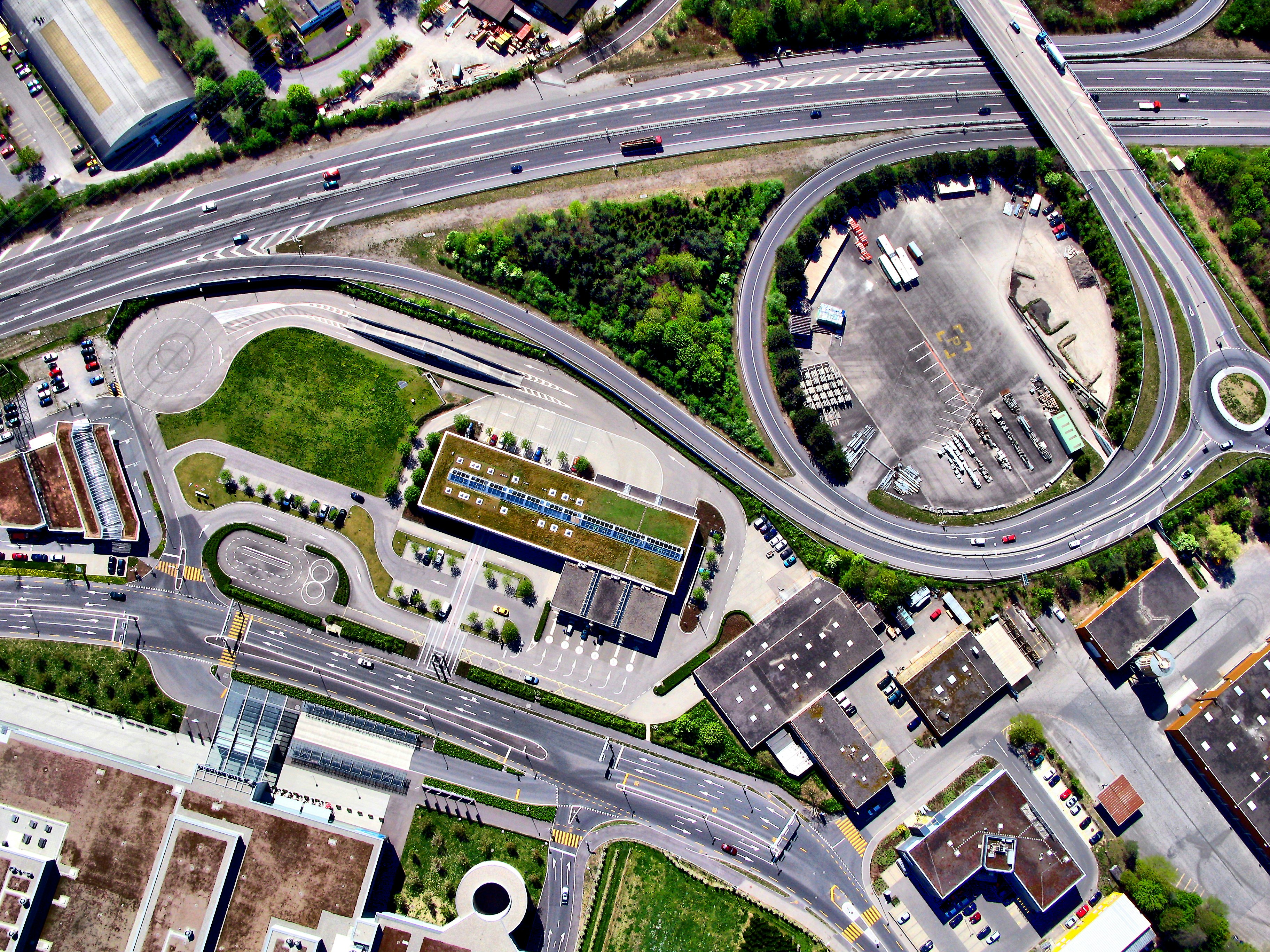 Aerial view showcasing the intricate layout of roads intertwined with patches of greenery and urban structures. The scene highlights the harmony between infrastructure and nature.