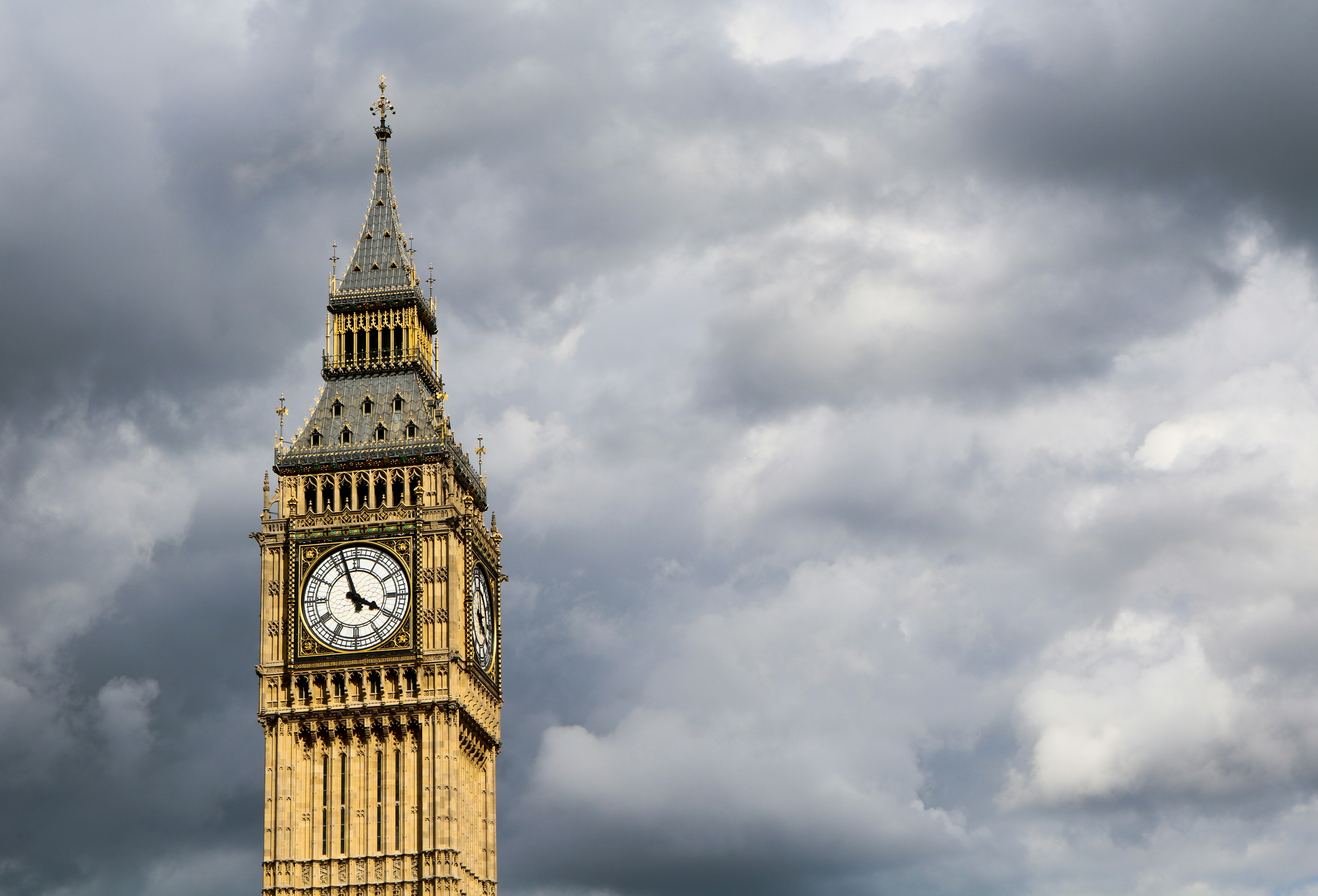 Clock tower with ornate details set against dramatic, overcast sky.