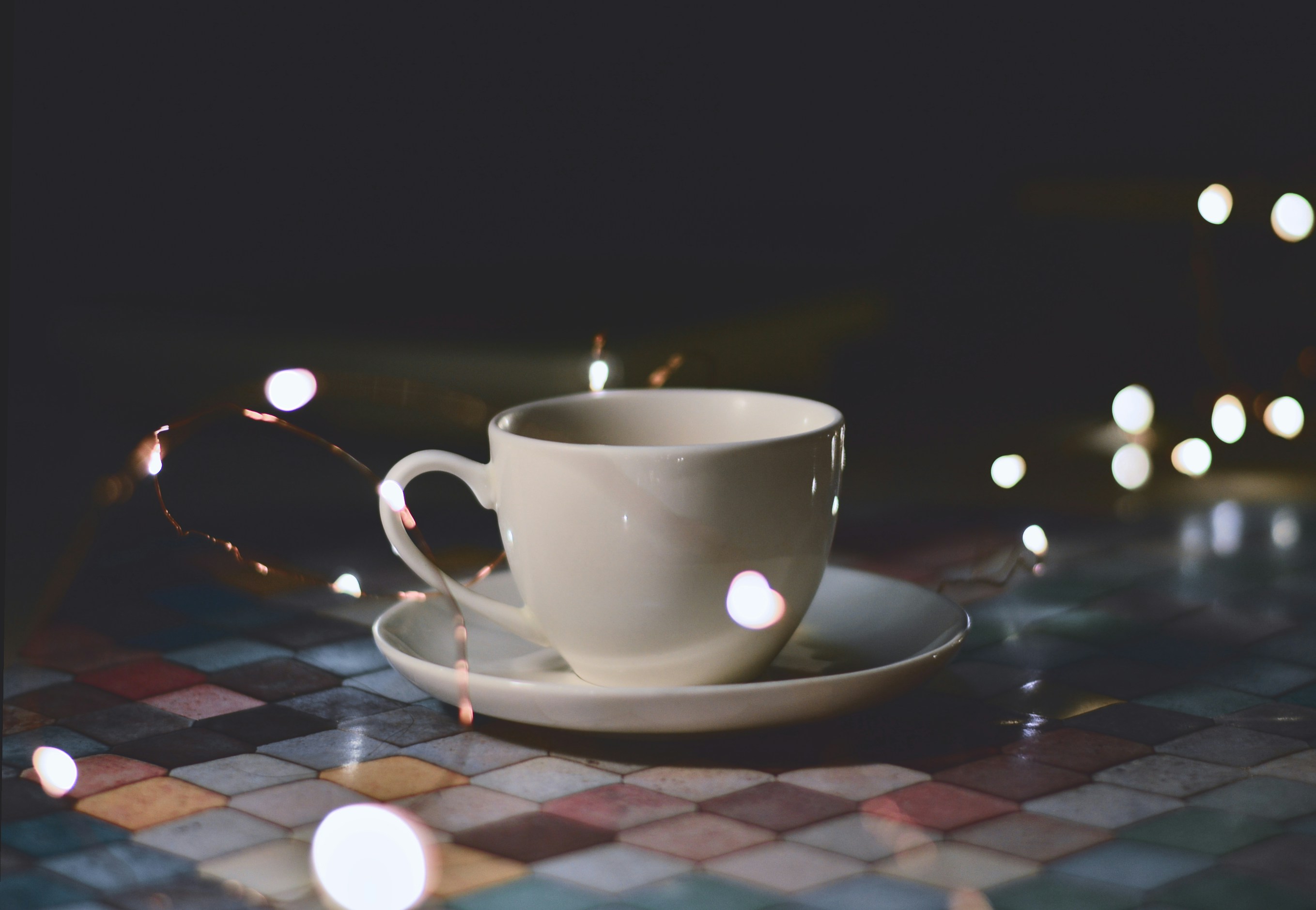 Night Cup on Mosaic Table: Quiet Focus Amid Sparkling Orbs