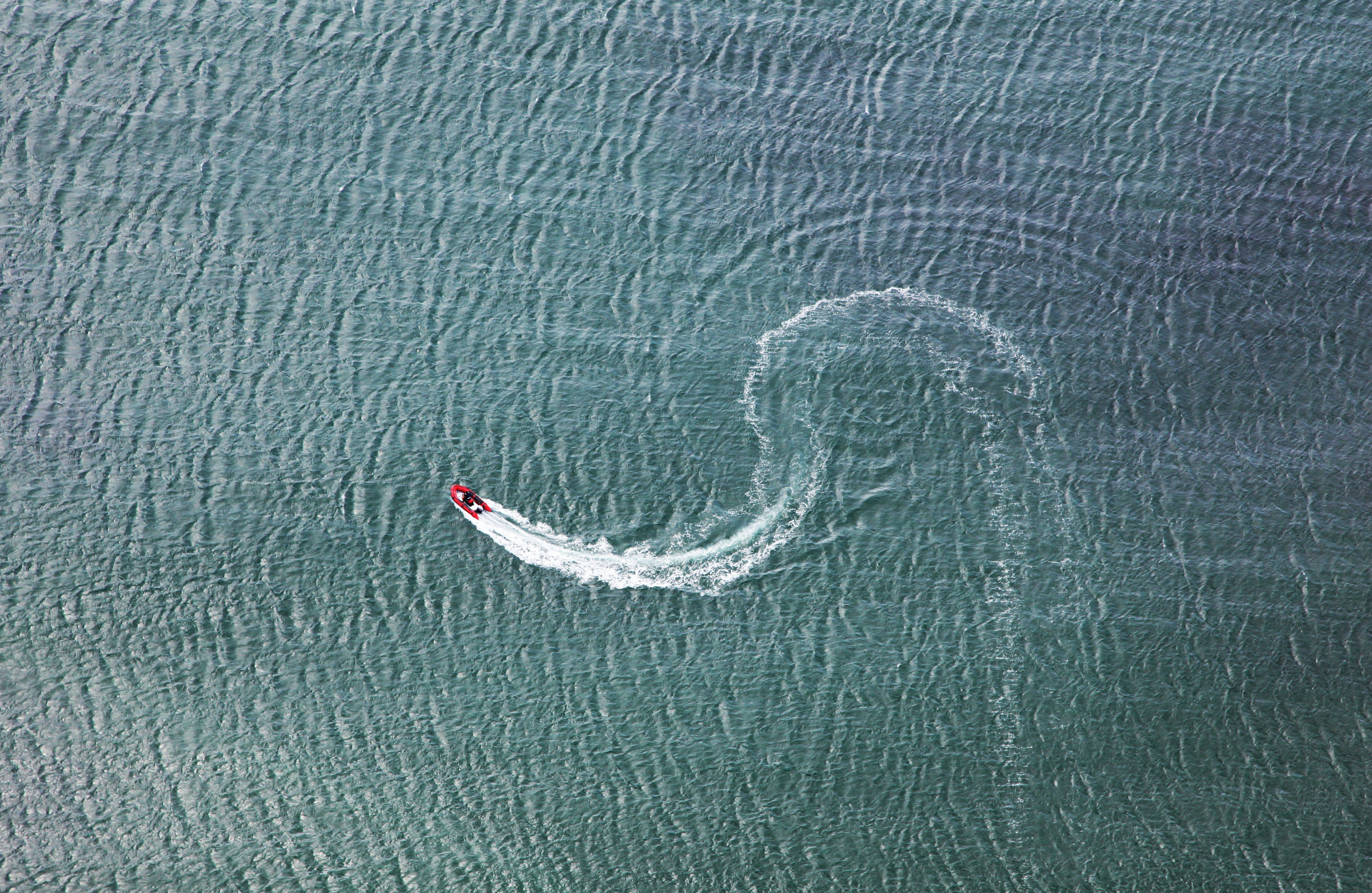 Crimson Speedboat Traces a White Crescent in Turquoise Ocean