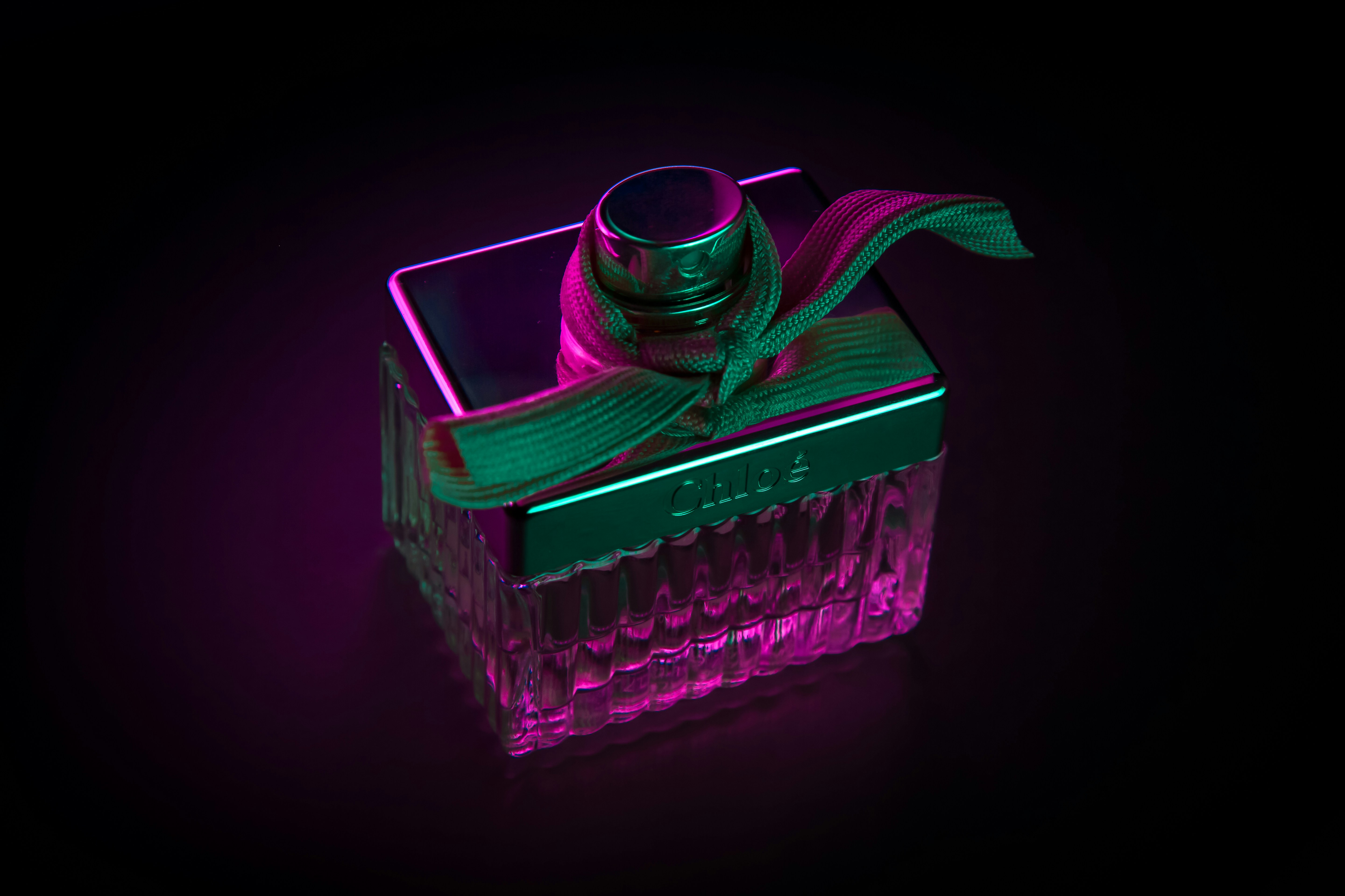 Emerald Ribbon Under Neon Magenta Glow: A Glass Perfume Bottle