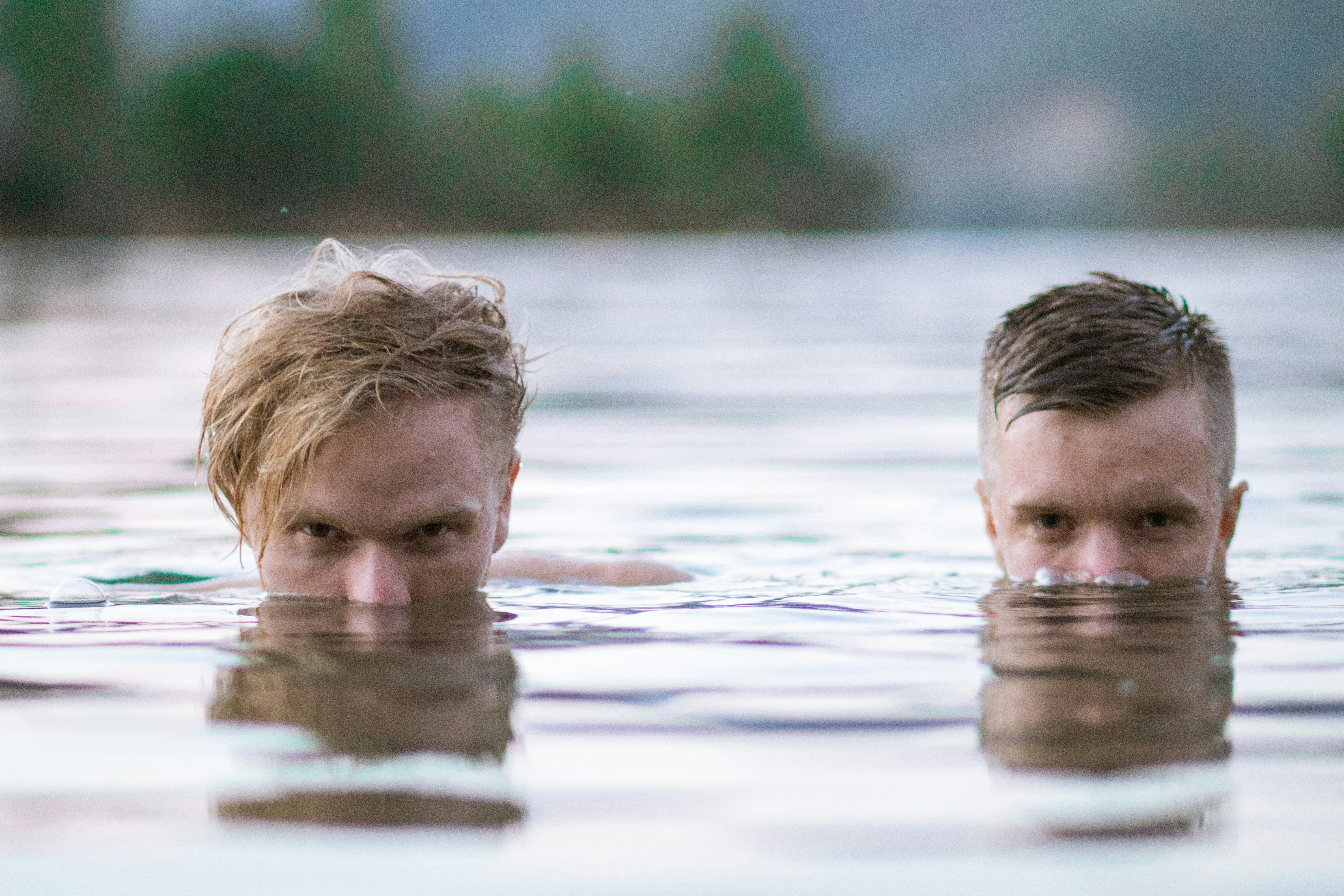Two men partially submerged in calm water with focused expressions.