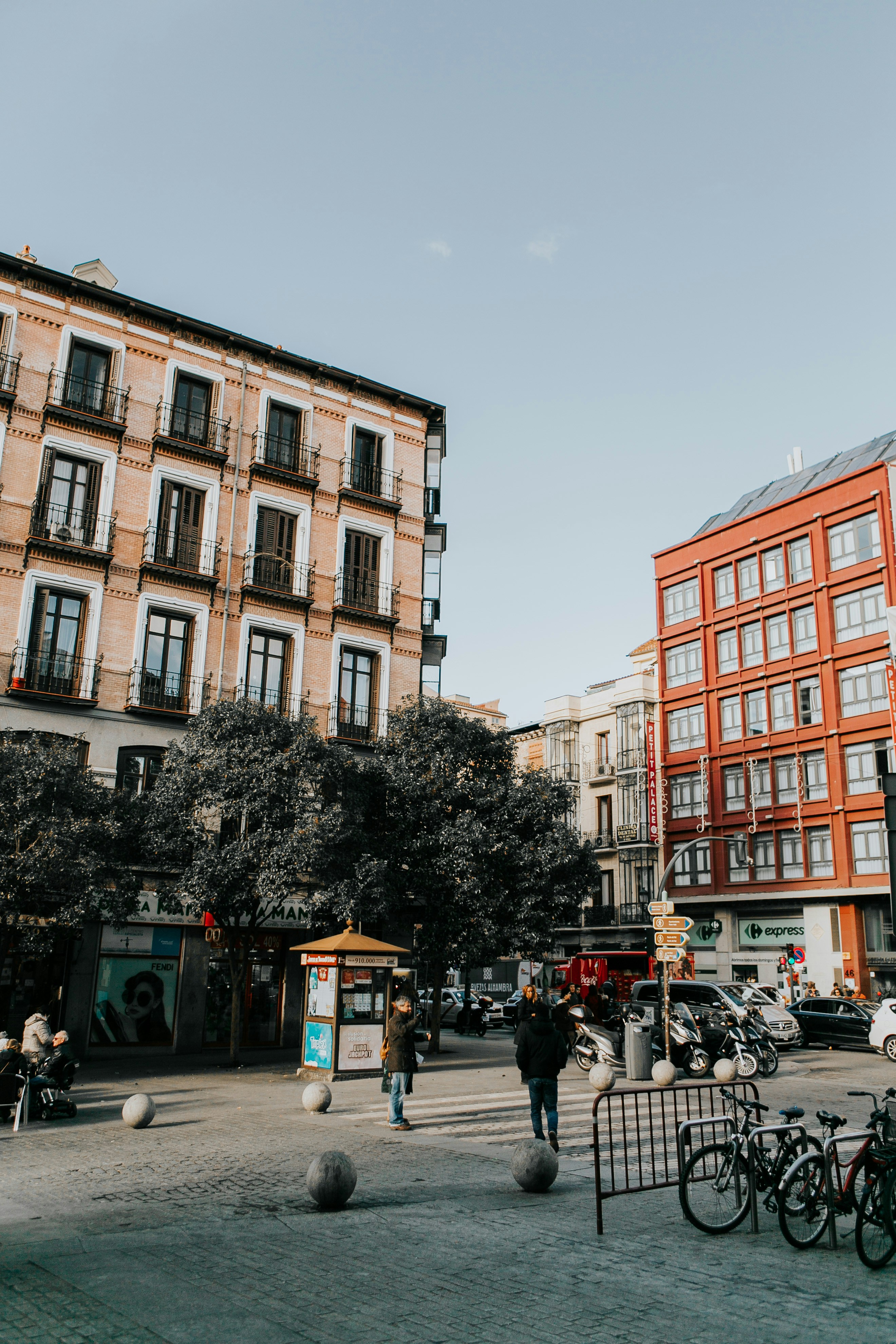 Charming city square featuring a blend of historic and modern buildings, with pedestrians and bicycles adding to the vibrant atmosphere.